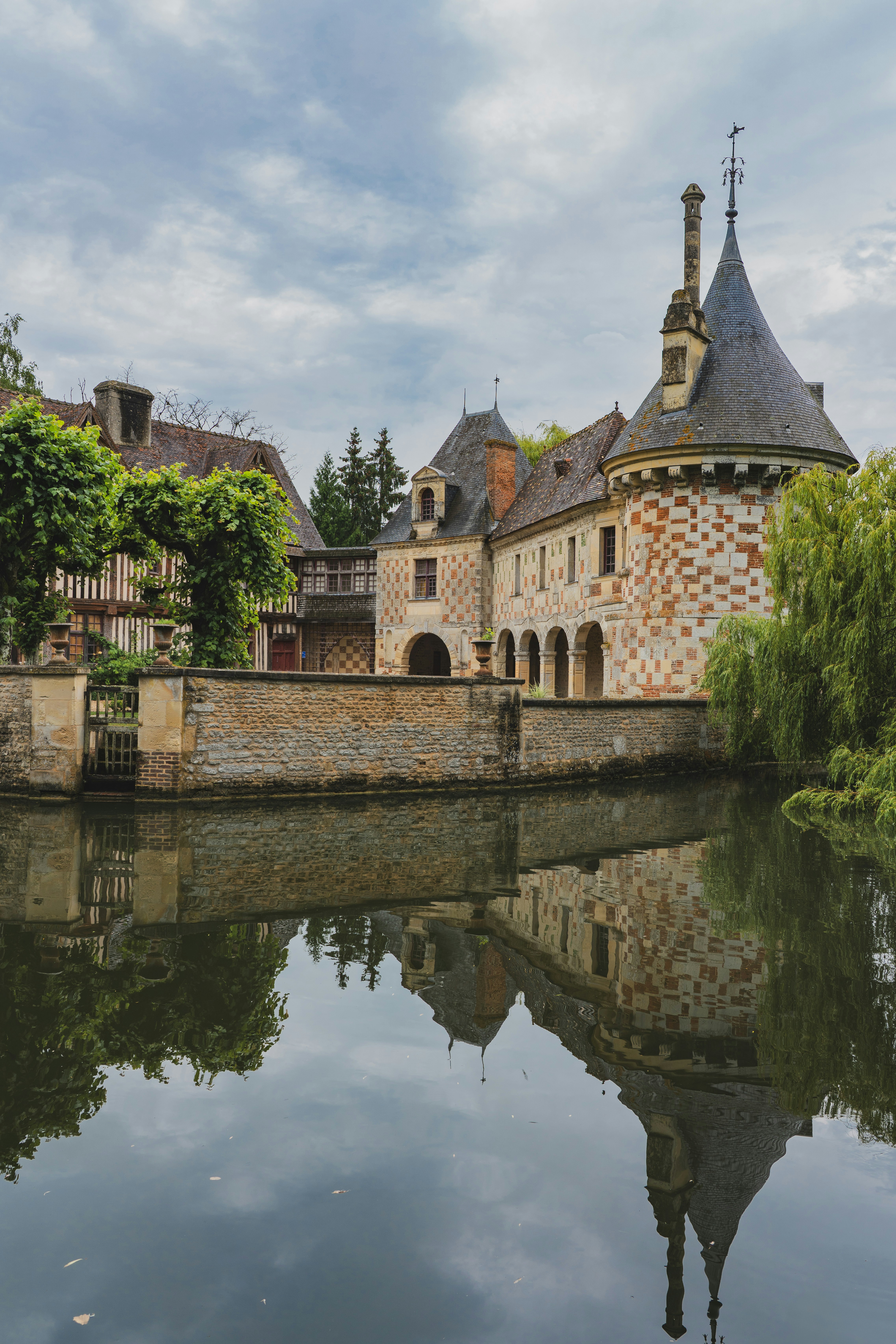 Chateau reflected in calm water under cloudy sky