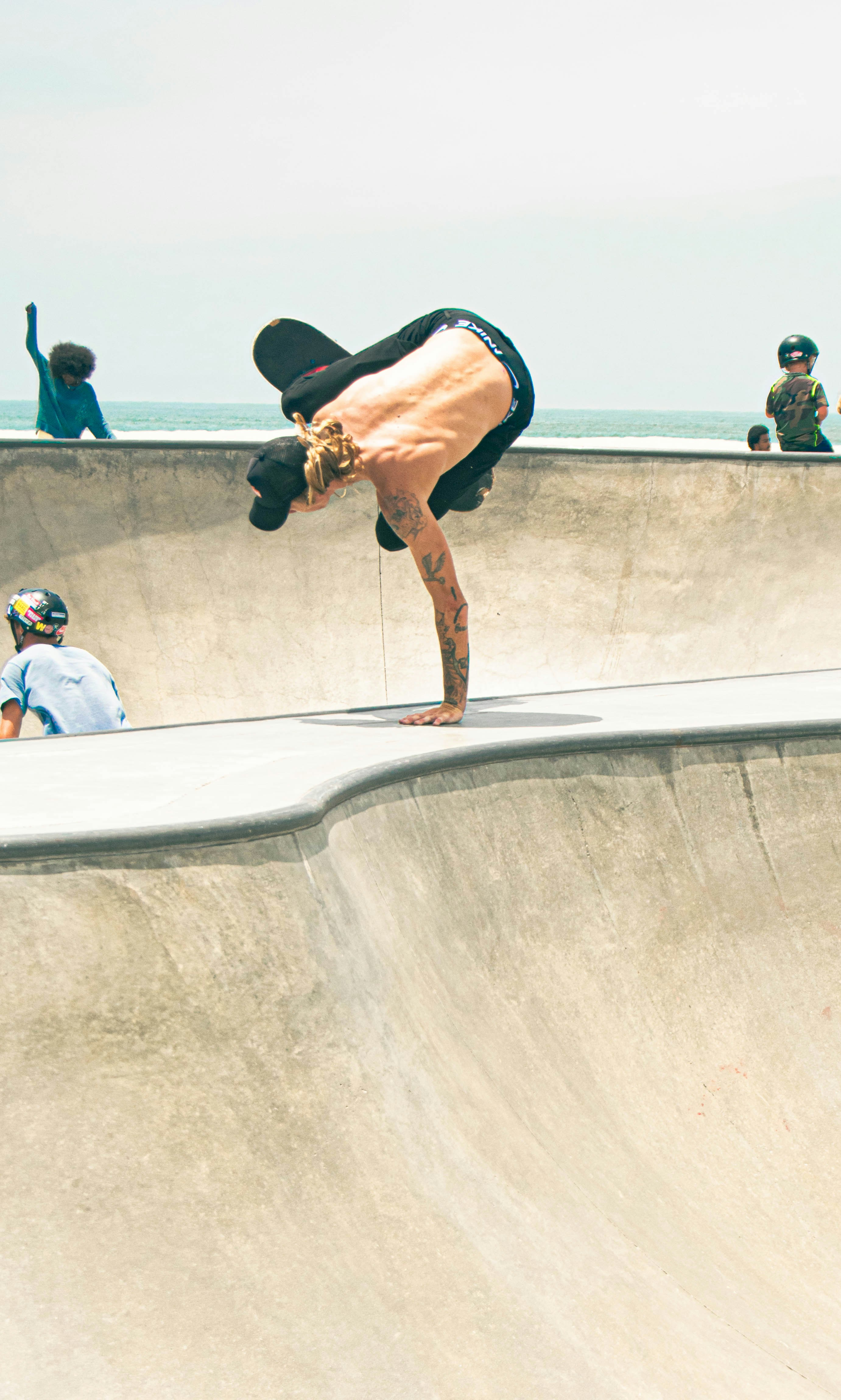 Skateboarder performs a handstand in a concrete skatepark. photo – Free ...