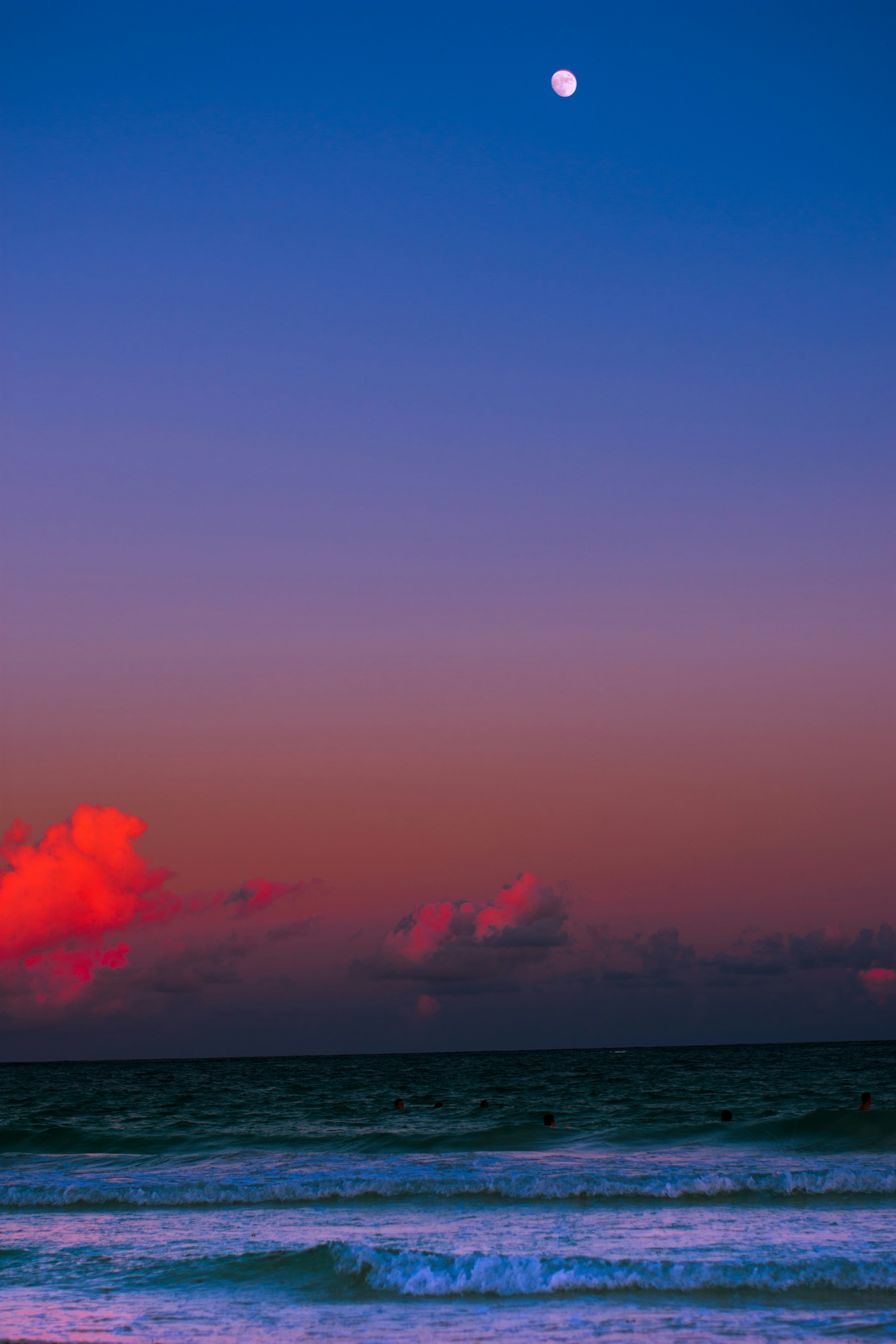 Moonlit ocean waves under a vibrant twilight sky