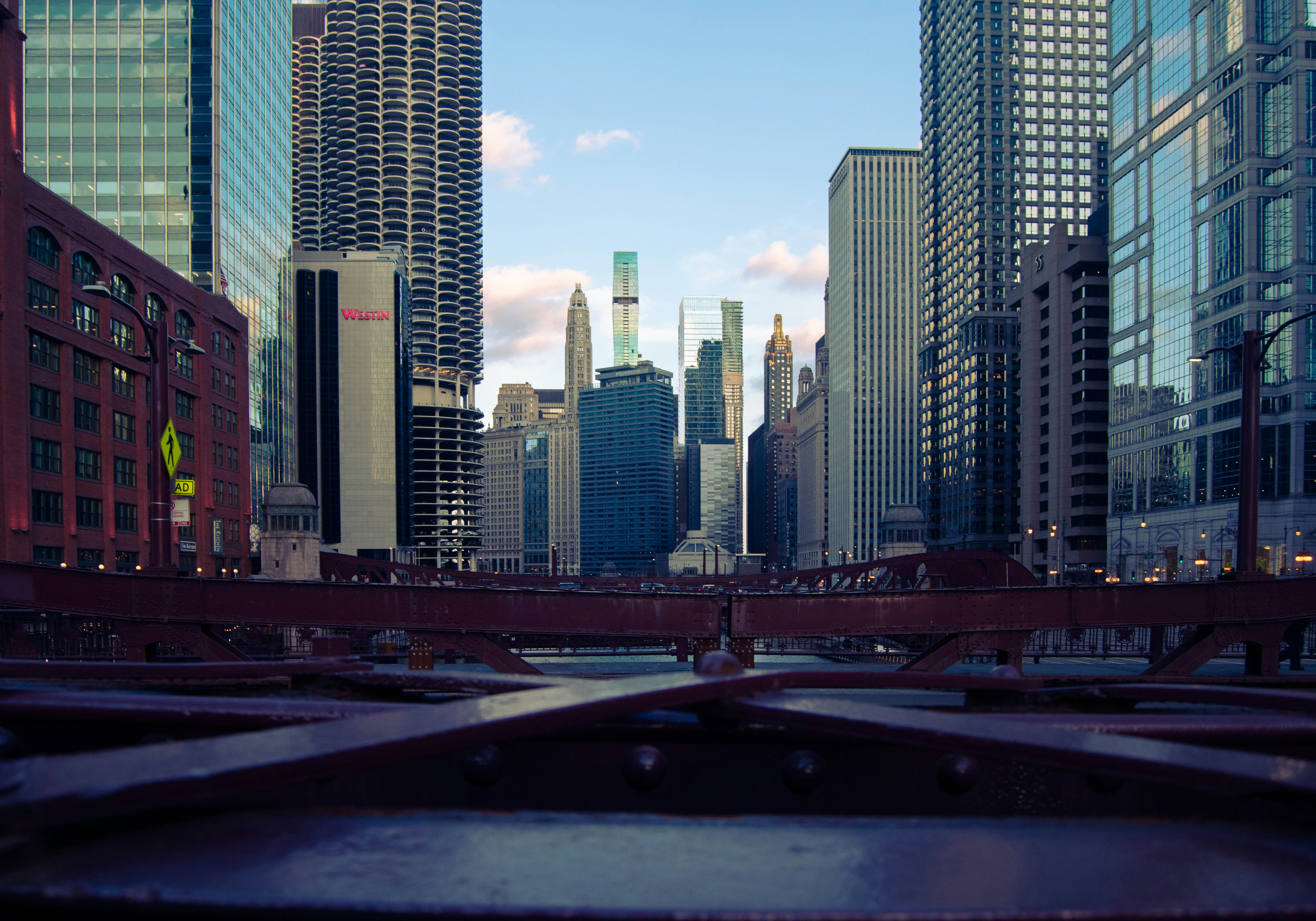 Modern skyscrapers line a city river with a bridge foreground.