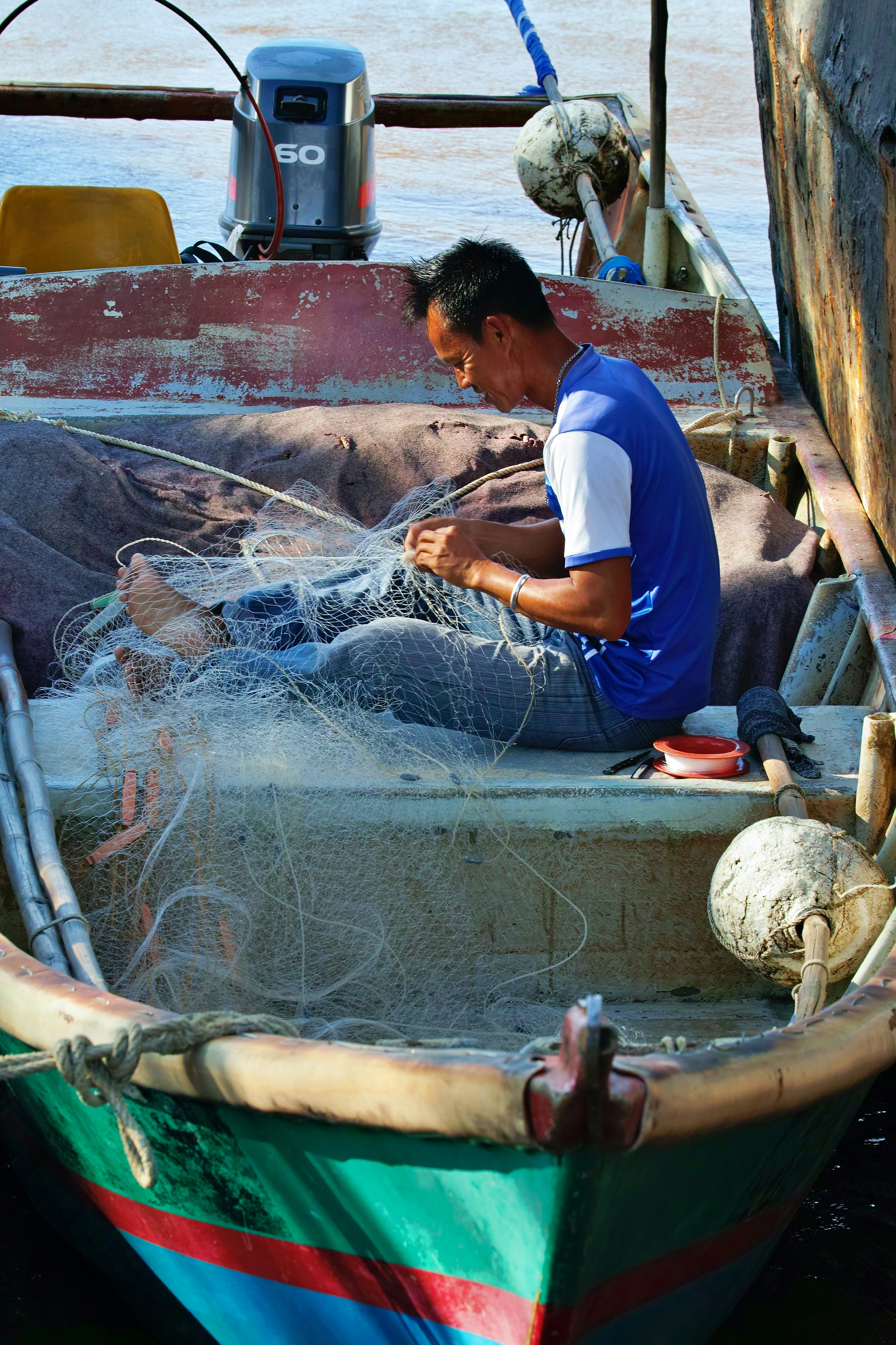 Pêcheur réparant un filet sur un bateau photo – Image gratuite de ...