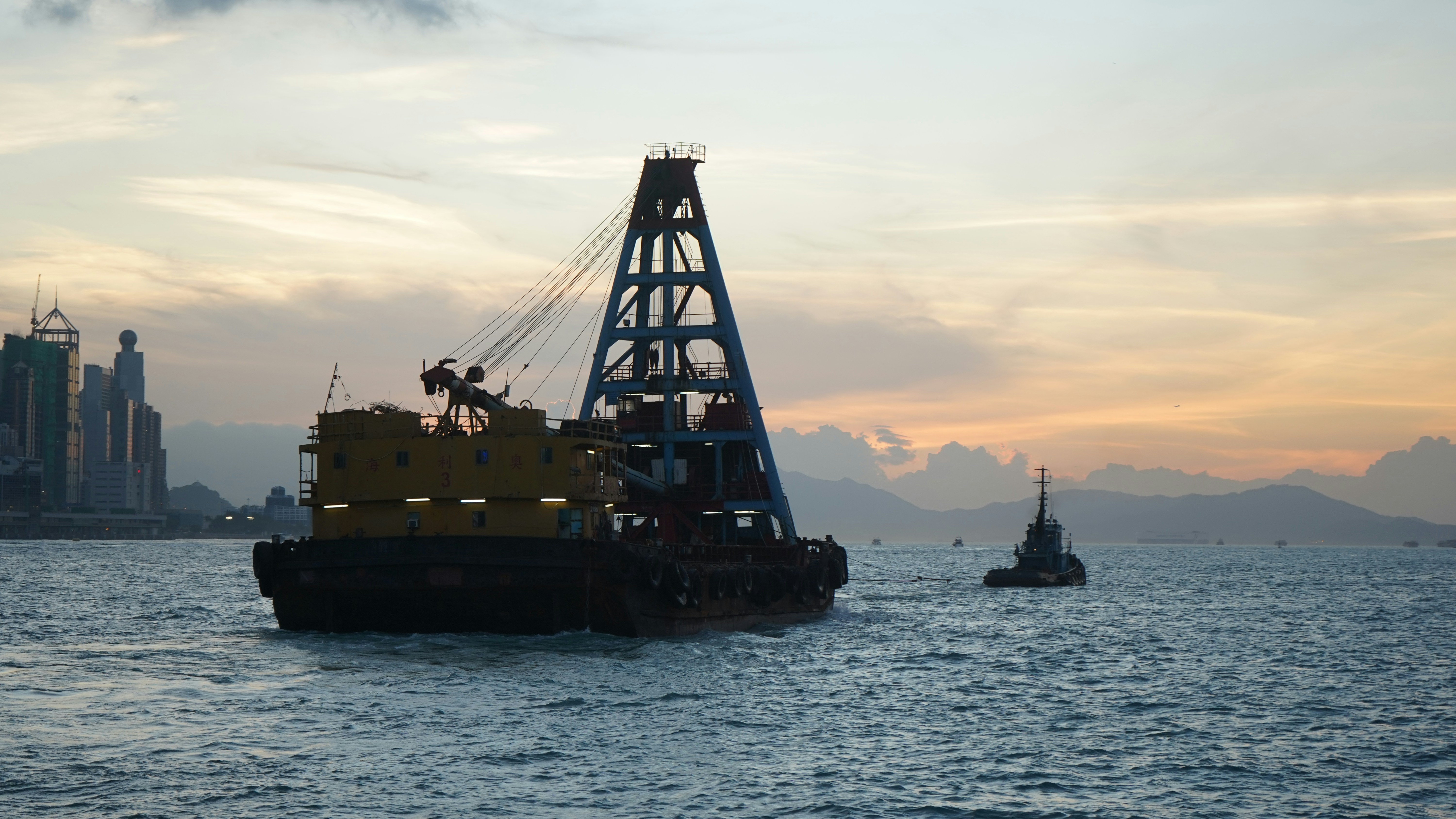 Industrial barge at sunset, Hong Kong waters | Crane barge and tugboat on the water at sunset