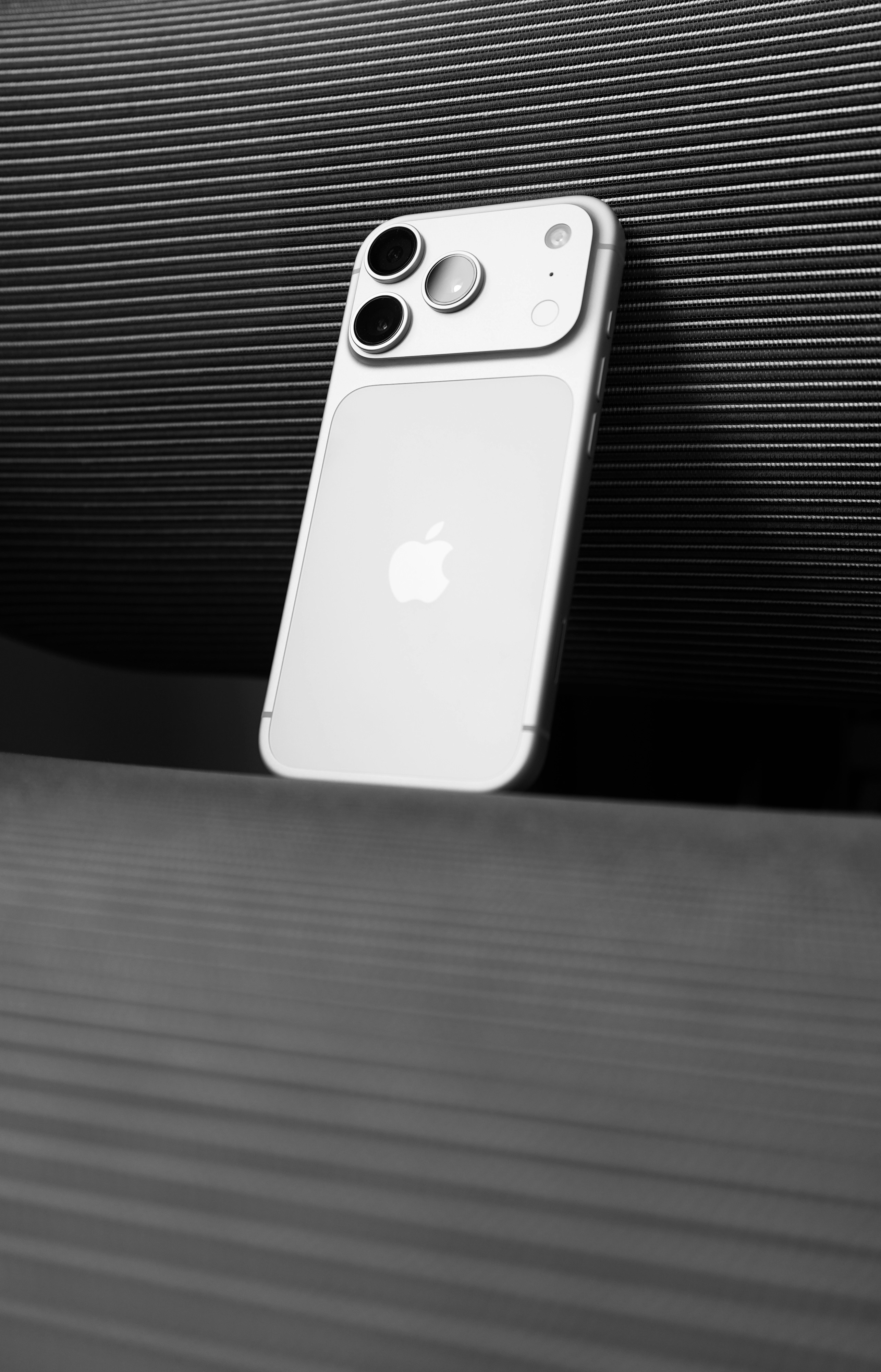 Silver smartphone with apple logo against striped background.