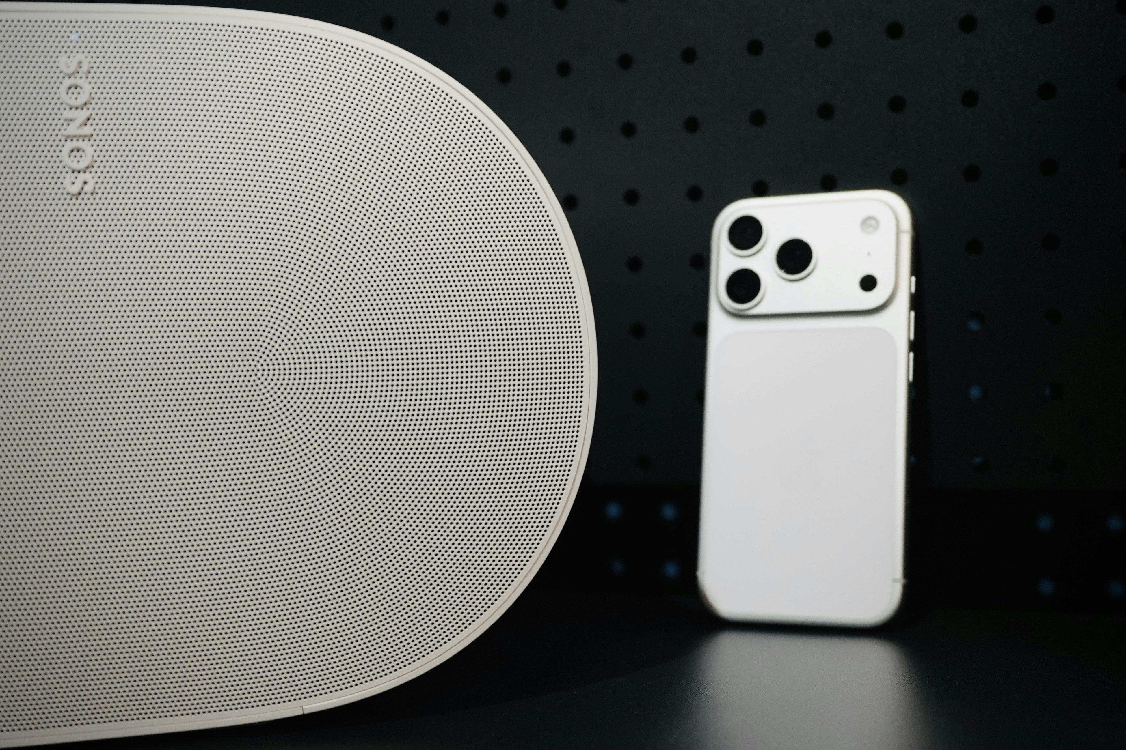 White sonos speaker and iPhone on dark background