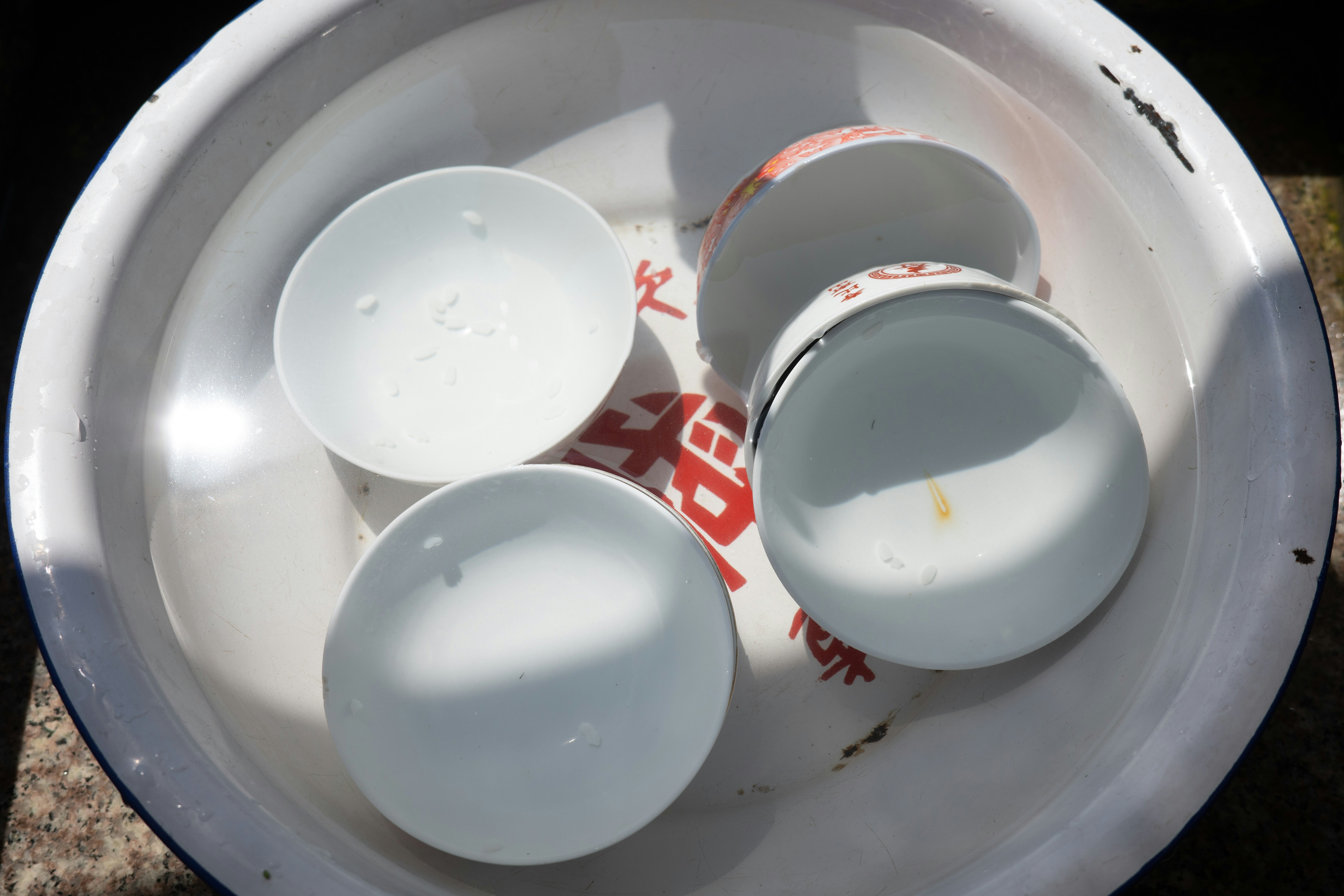 Four small bowls floating in a large basin of water.