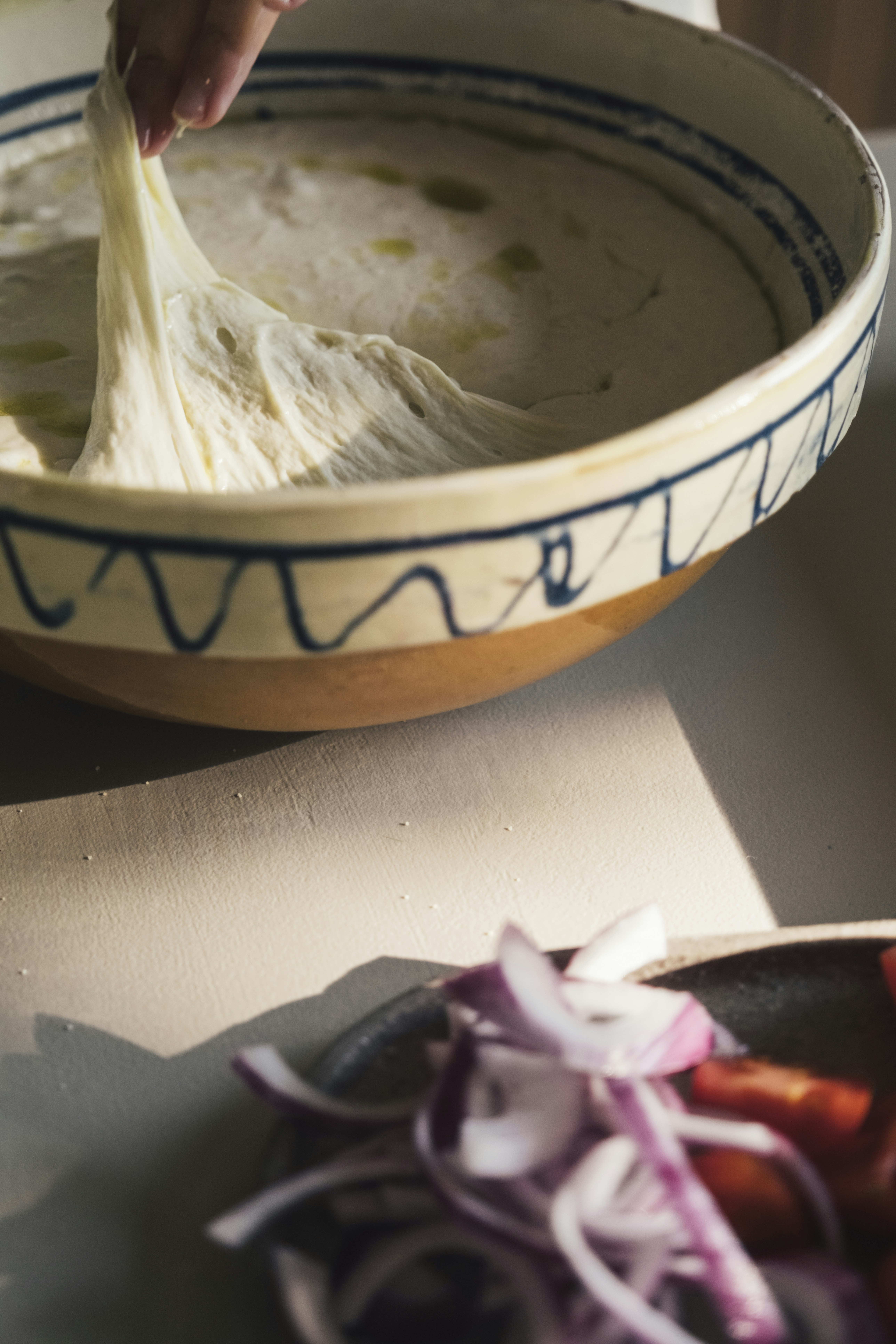 Stretching Cream: A Hand-Tug of Cheese Over a Rustic Ceramic Bowl