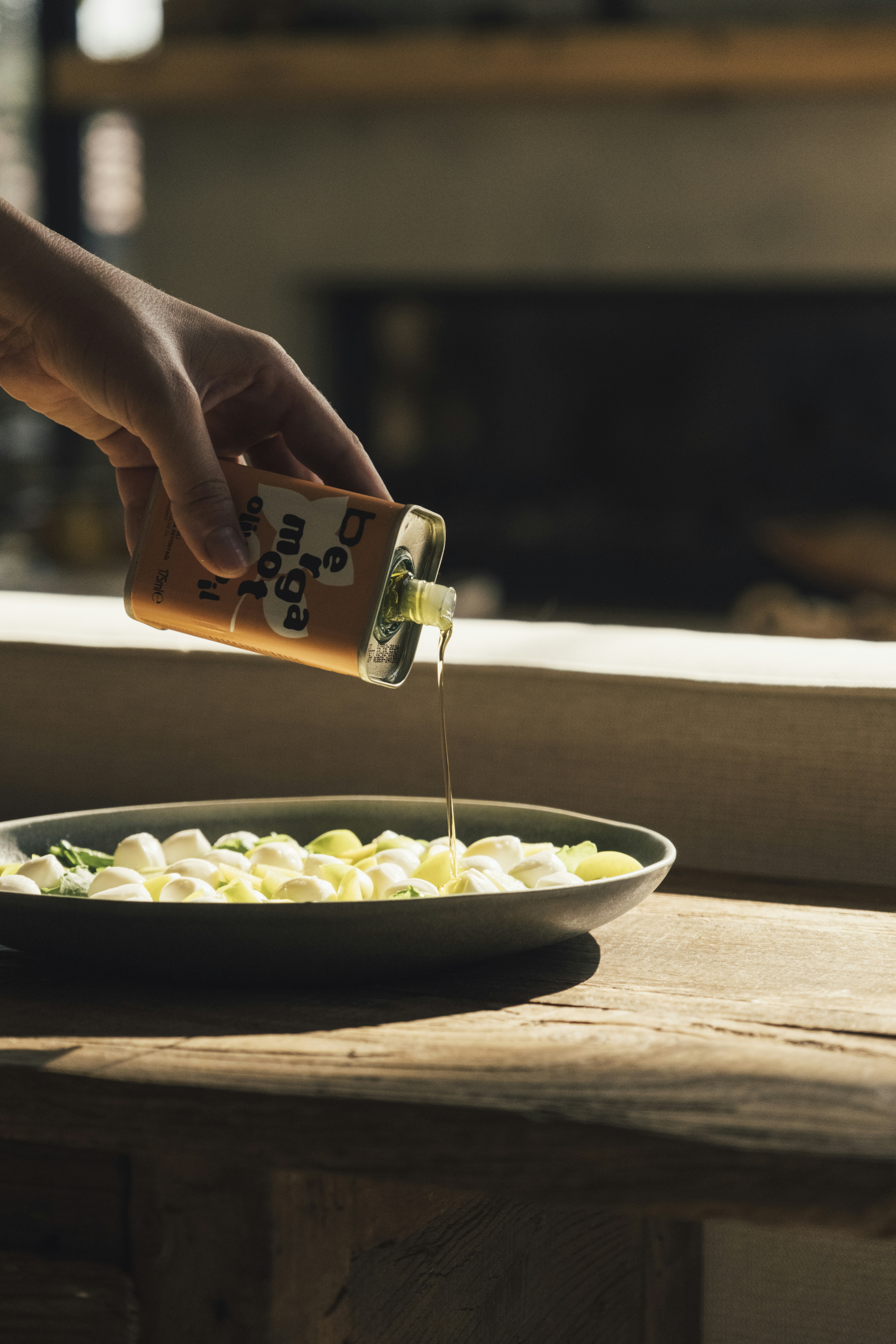 Amber Drizzle in Sunlight: Hand Pours Oil onto a Rustic Plate of Bite-Sized Morsels