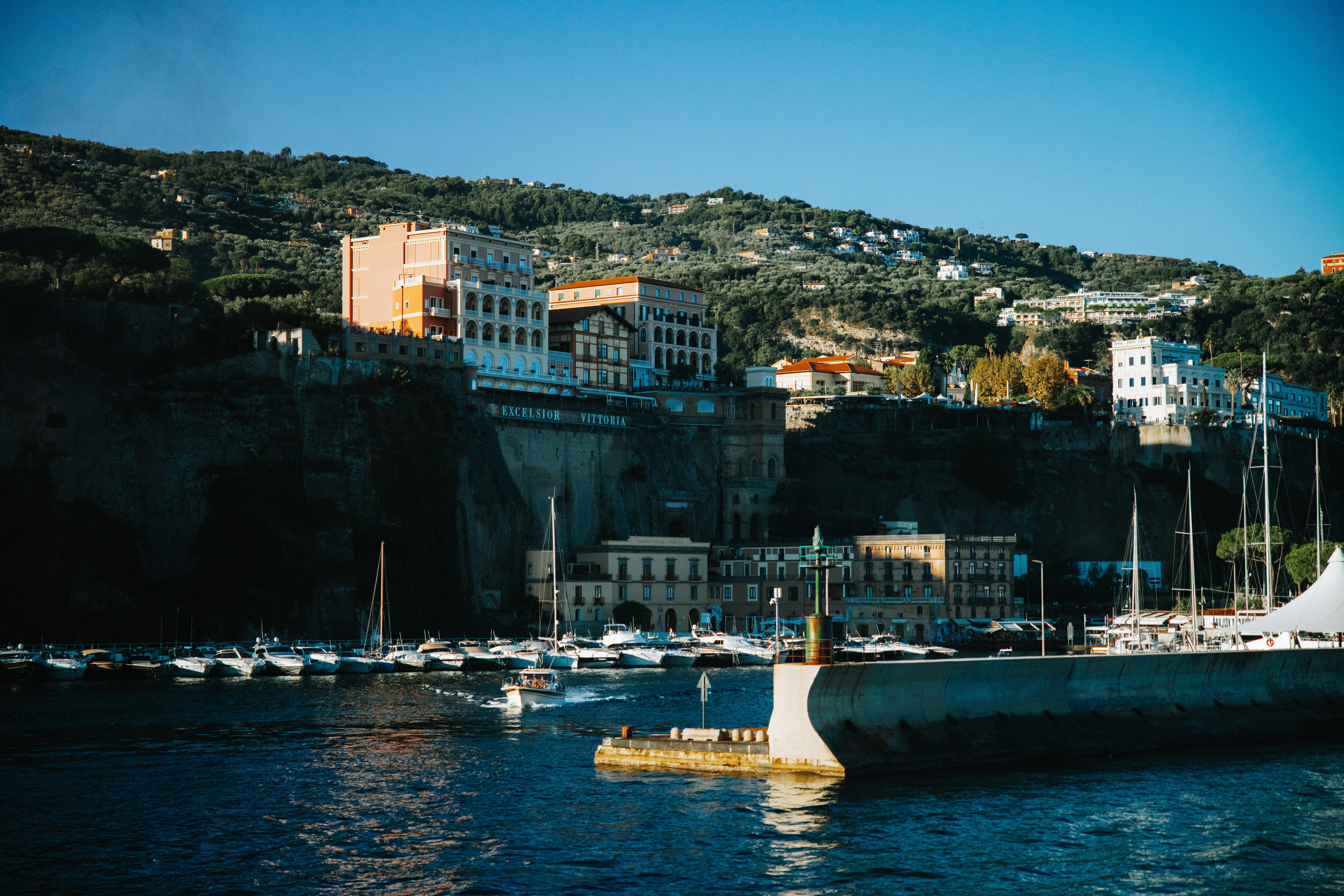 Boats docked in a harbor with buildings on a hillside.