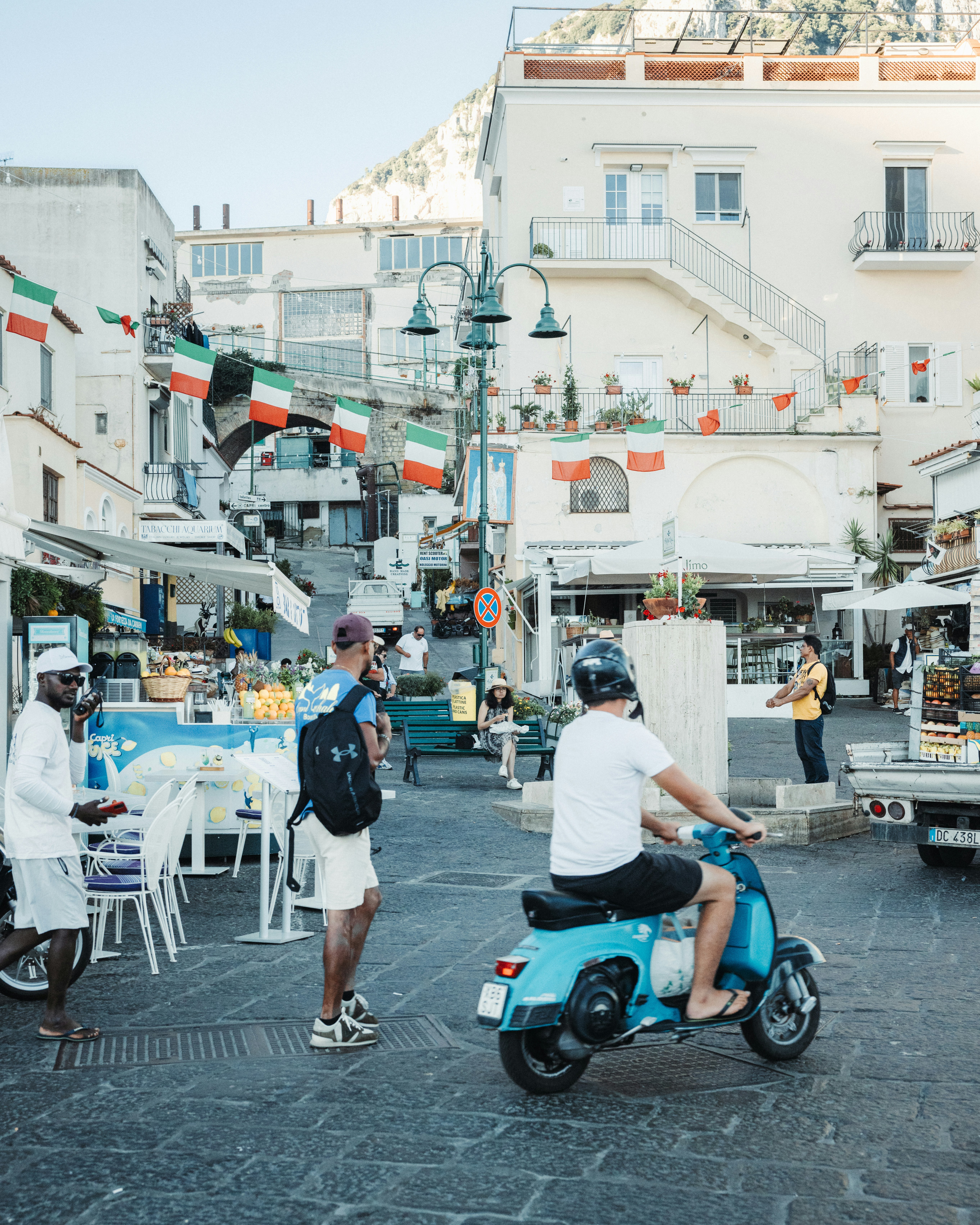 Blue Vespa in a Sunlit Italian Piazza Beneath Fluttering Flags