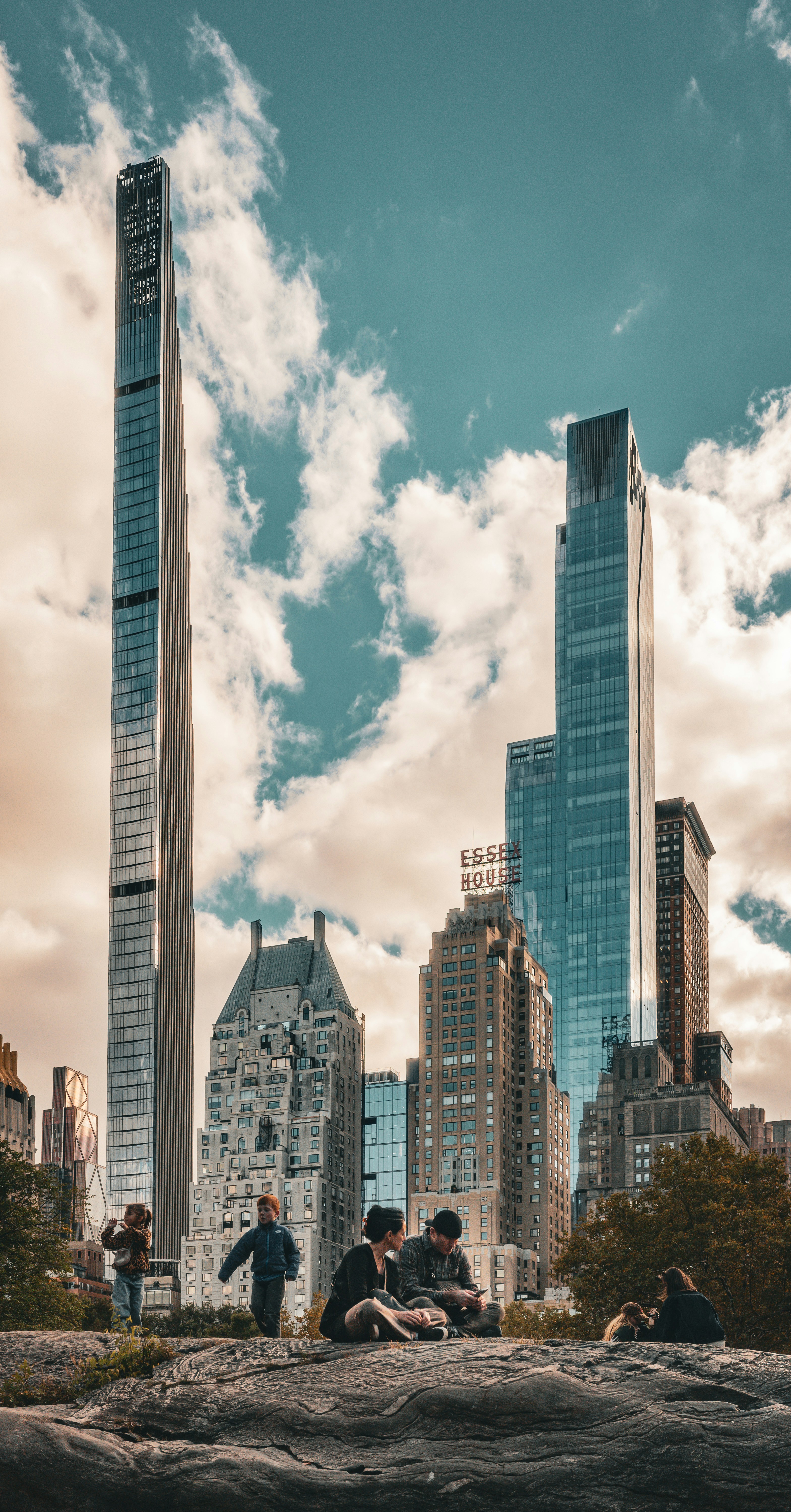 NYC Central Park / Umpire Rock | People relax on rocks with city skyline background