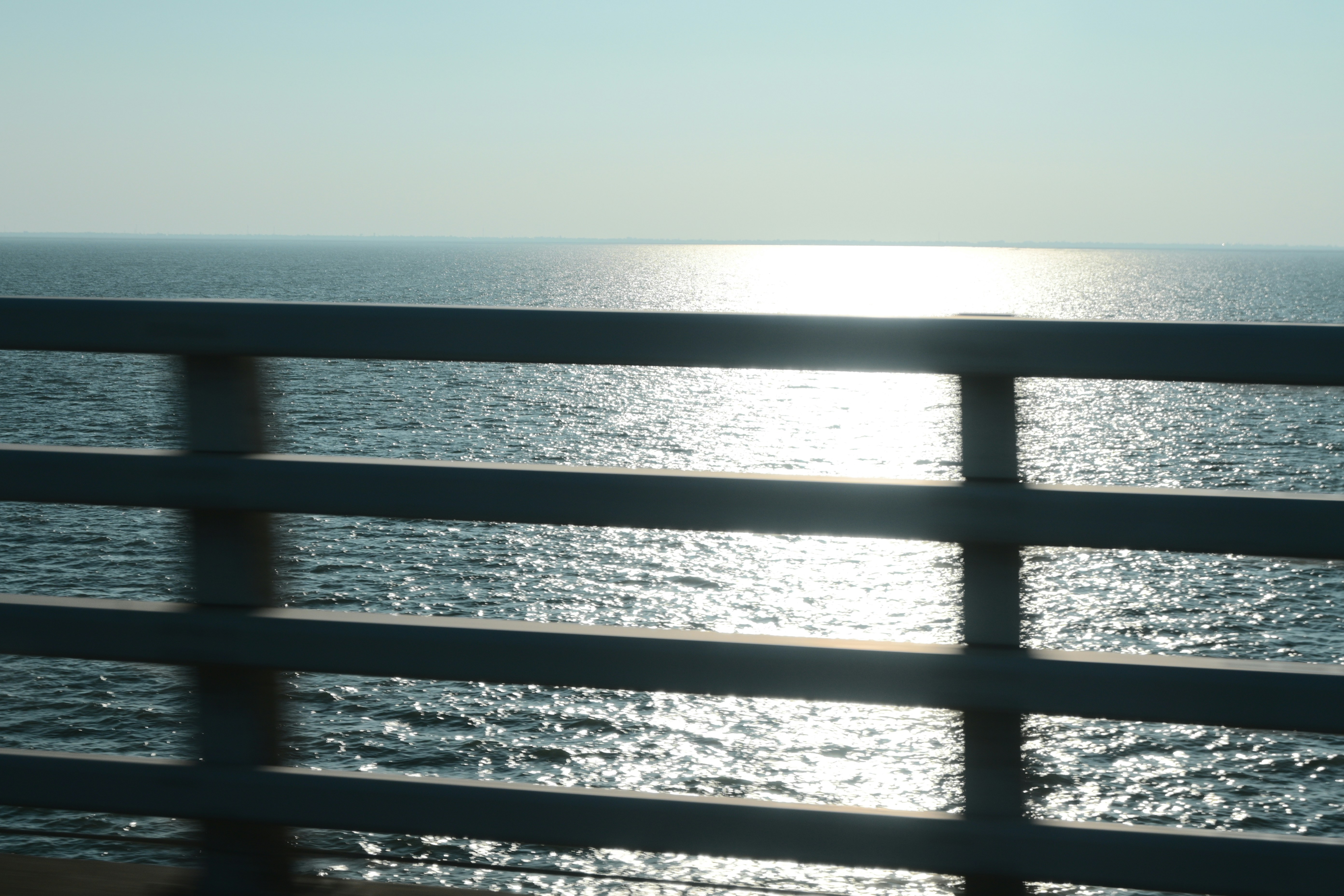Sunlight glinting on the ocean waves behind railing.