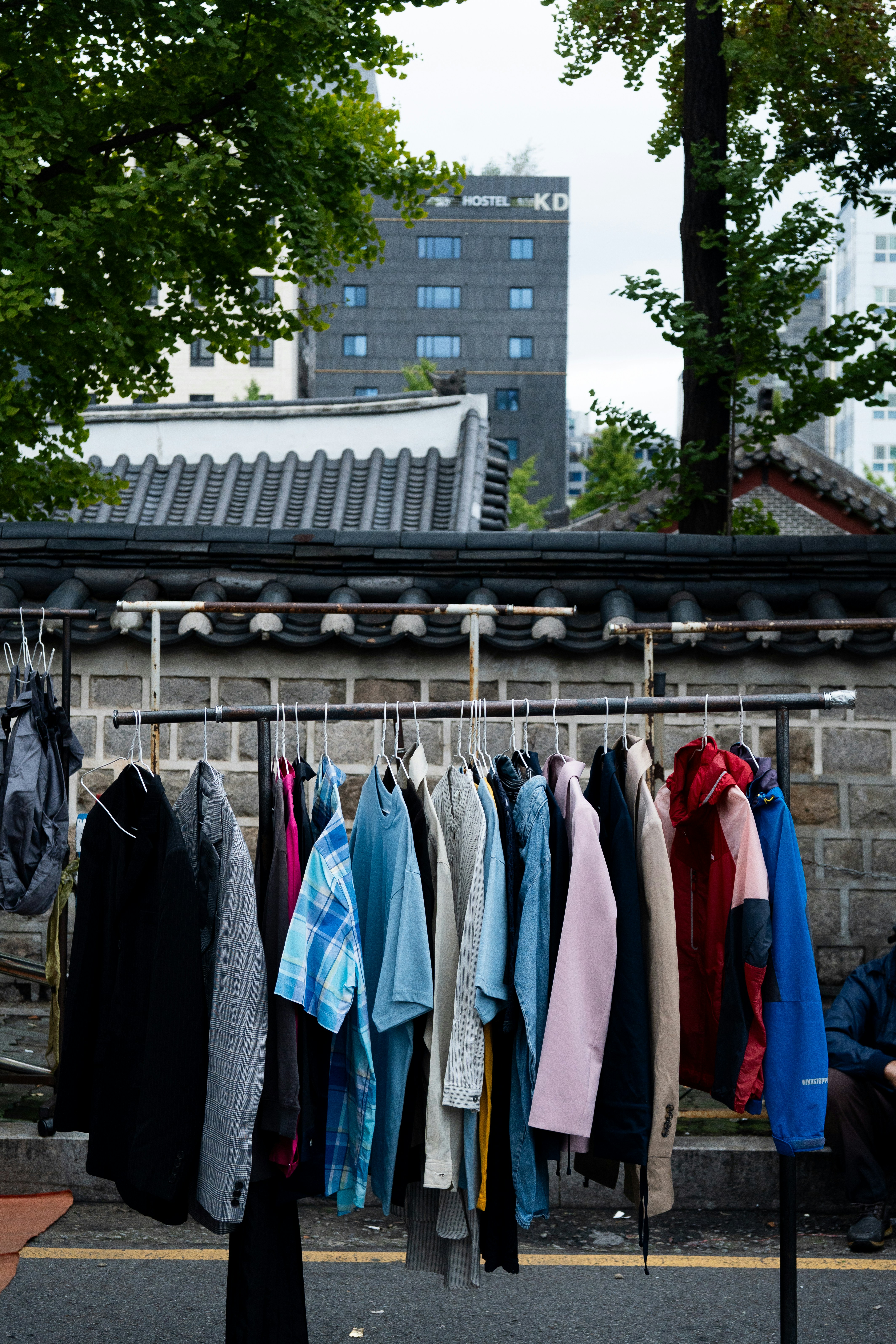 Korean Vintage Market Dongmyo | Clothes hanging on a rack outside a building.