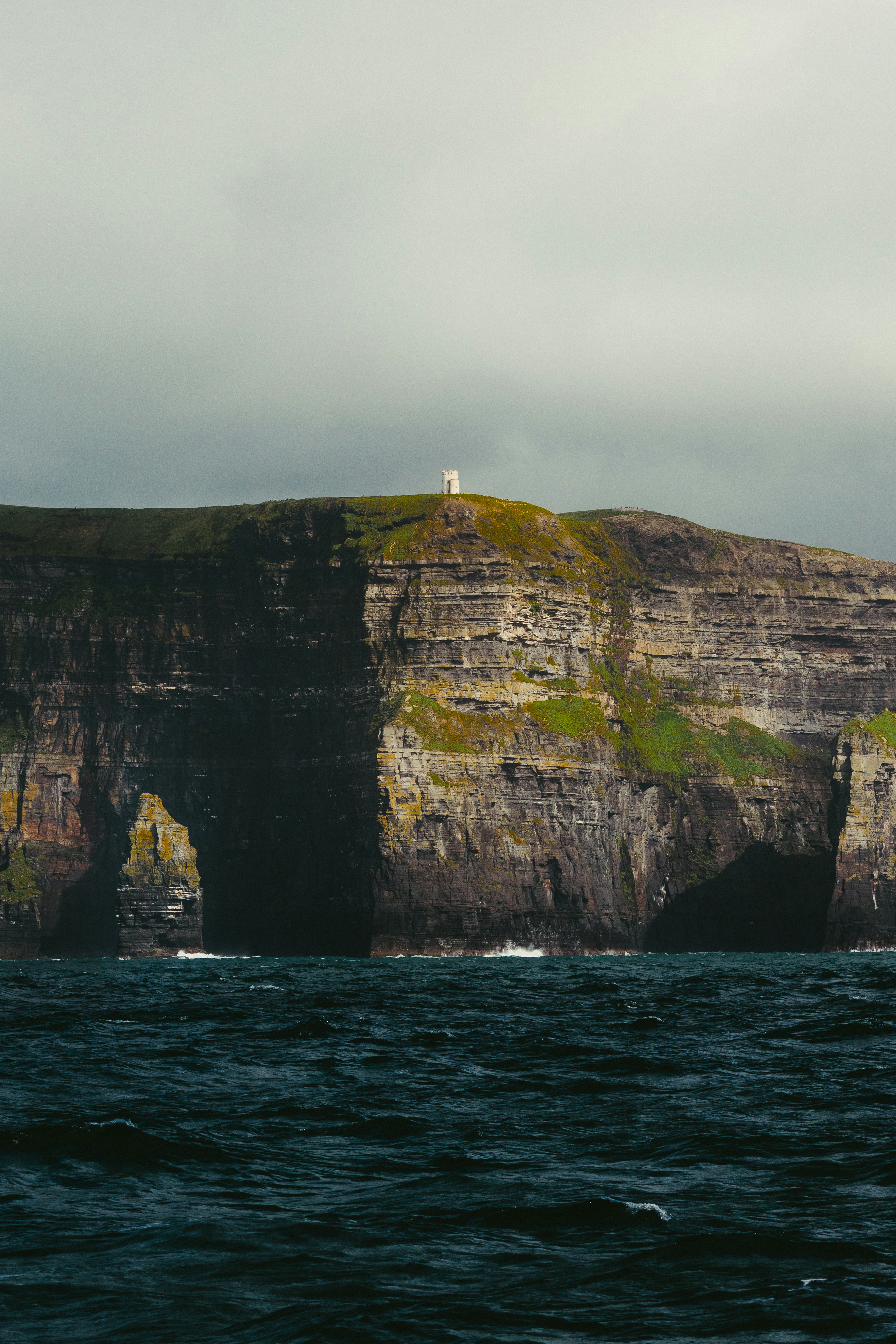 Dramatic cliffs with a lighthouse under a cloudy sky