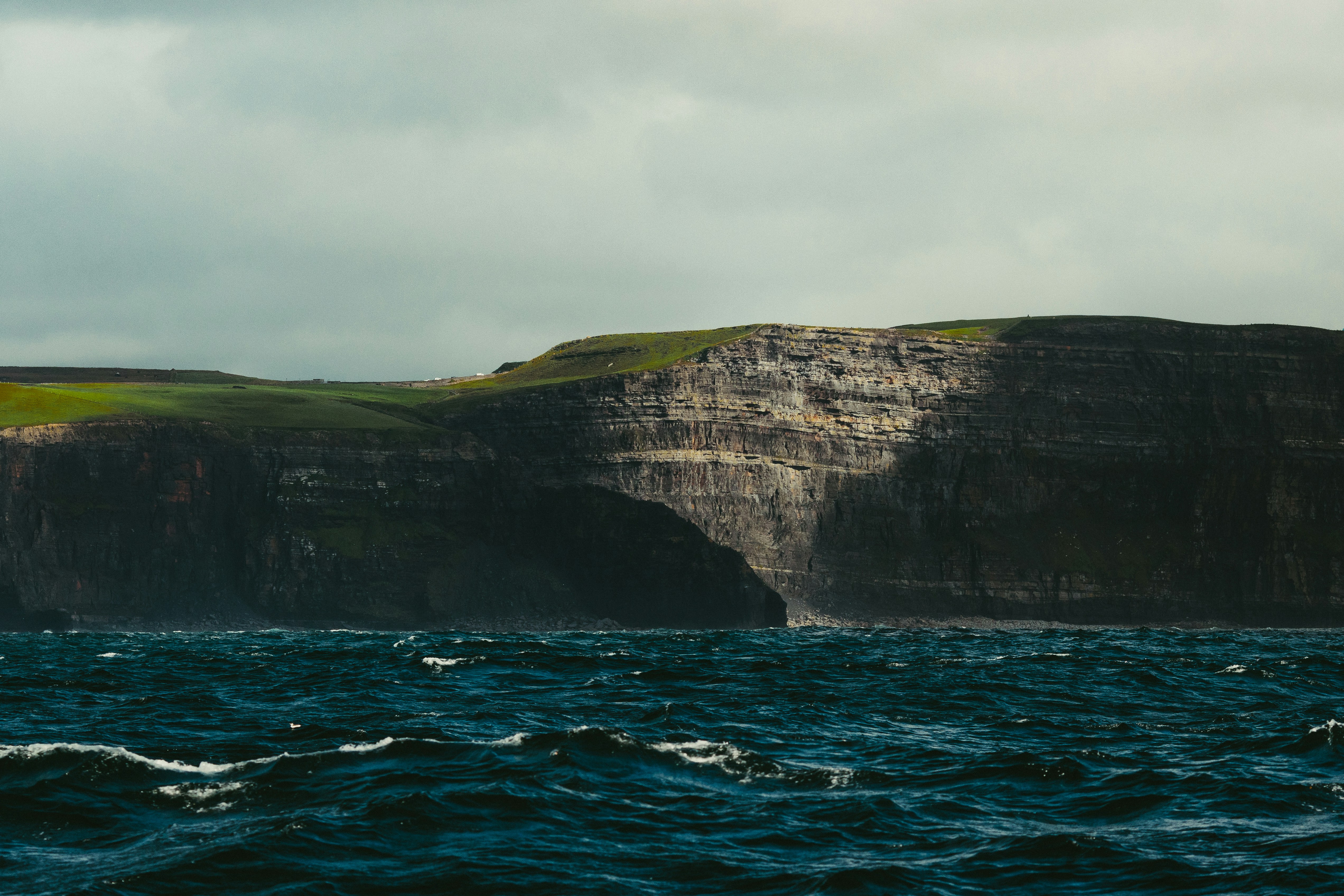 Dramatic cliffs rise above a choppy blue ocean.