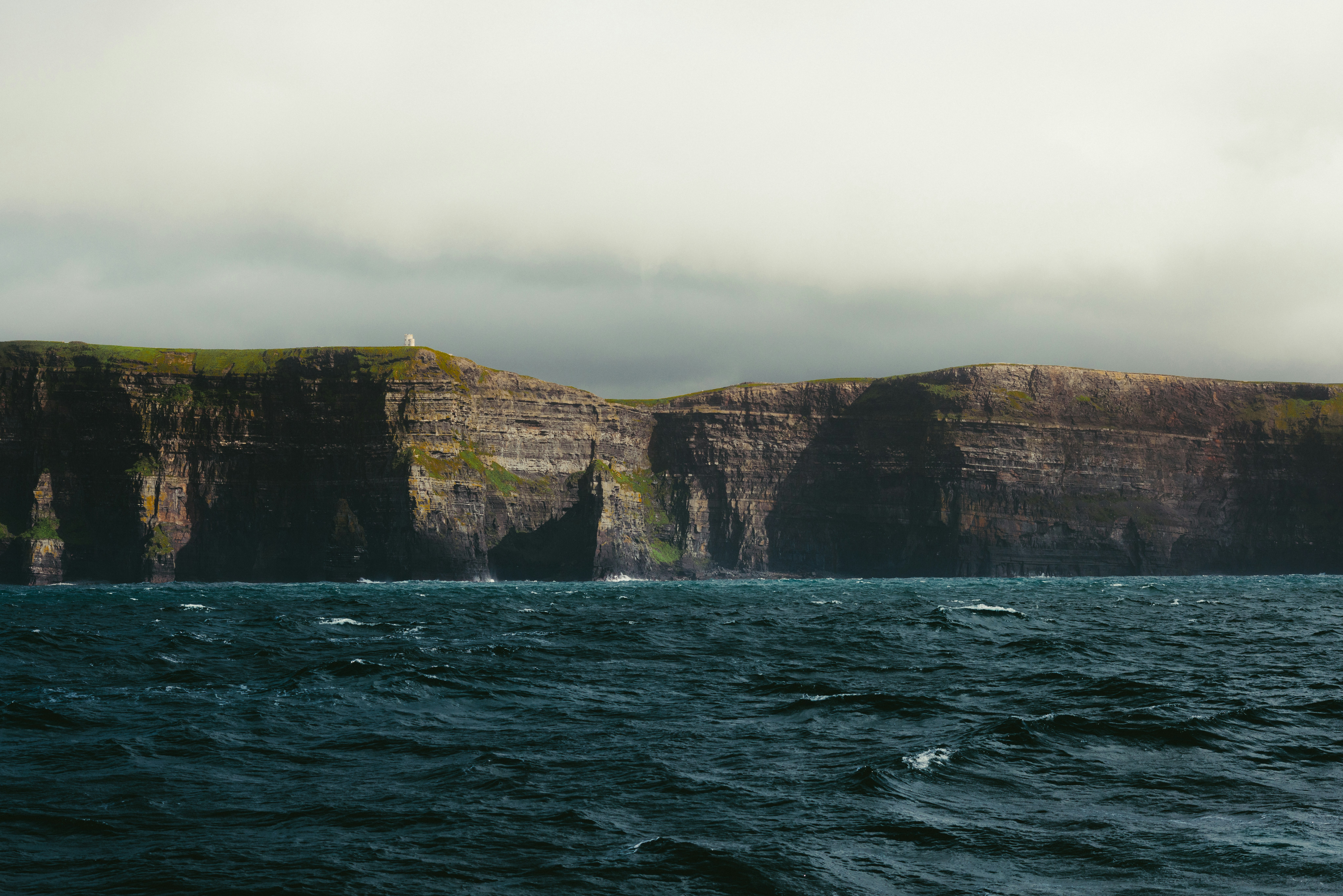 Rugged cliffs rise above a choppy blue ocean.