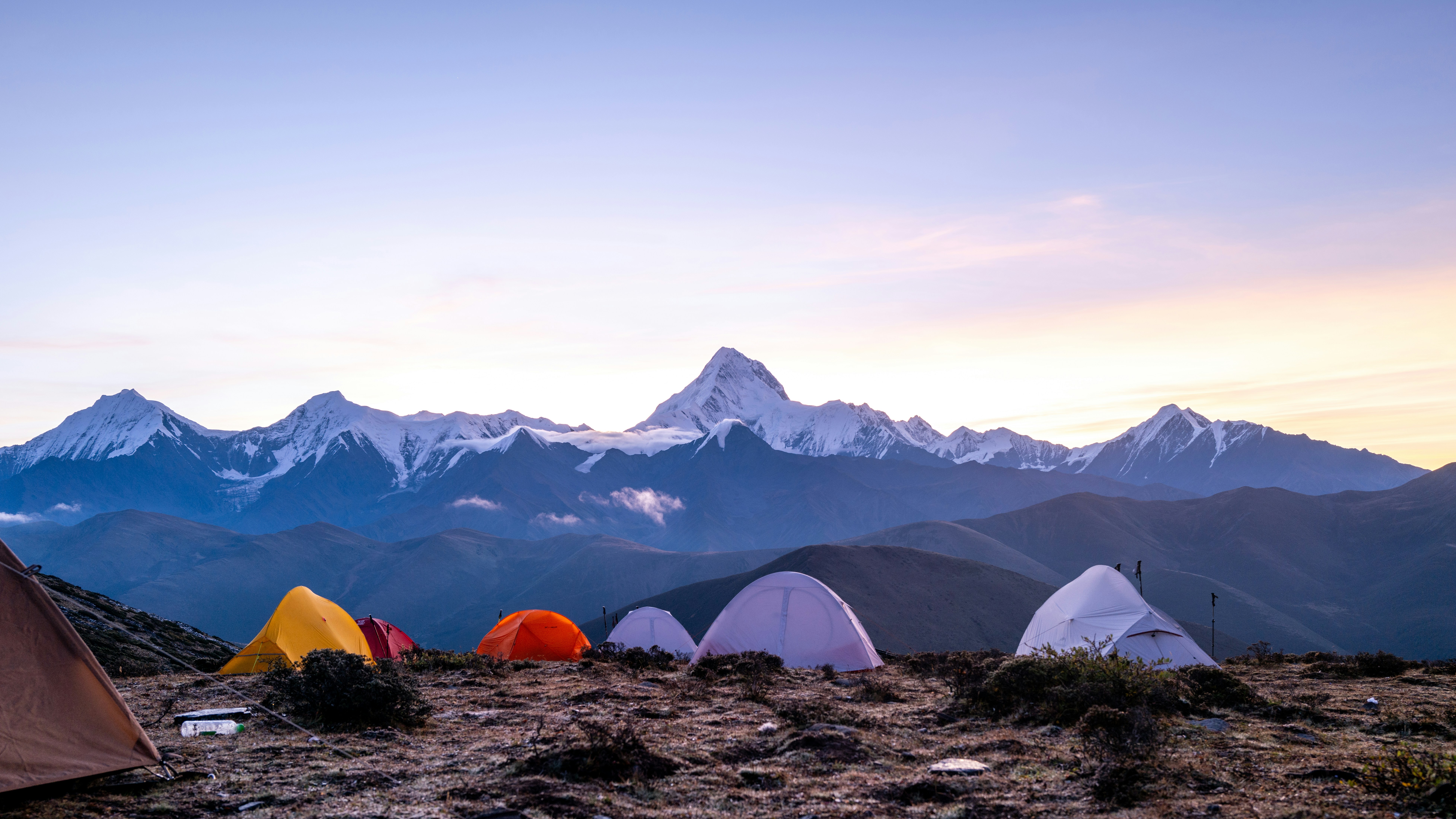 Colorful tents set up on a mountain ridge at sunrise.