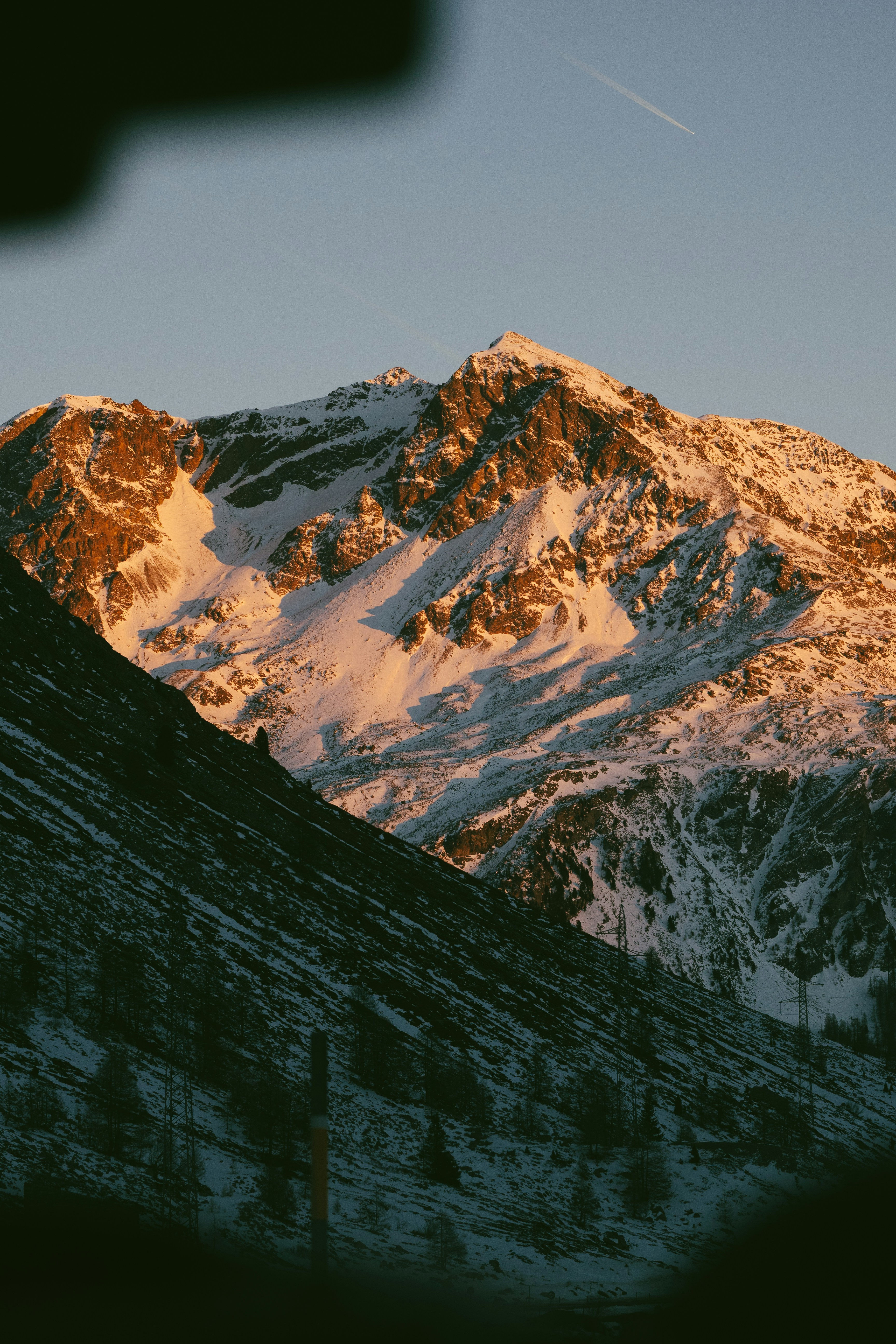 Snow-covered mountain peak illuminated by golden hour sunlight