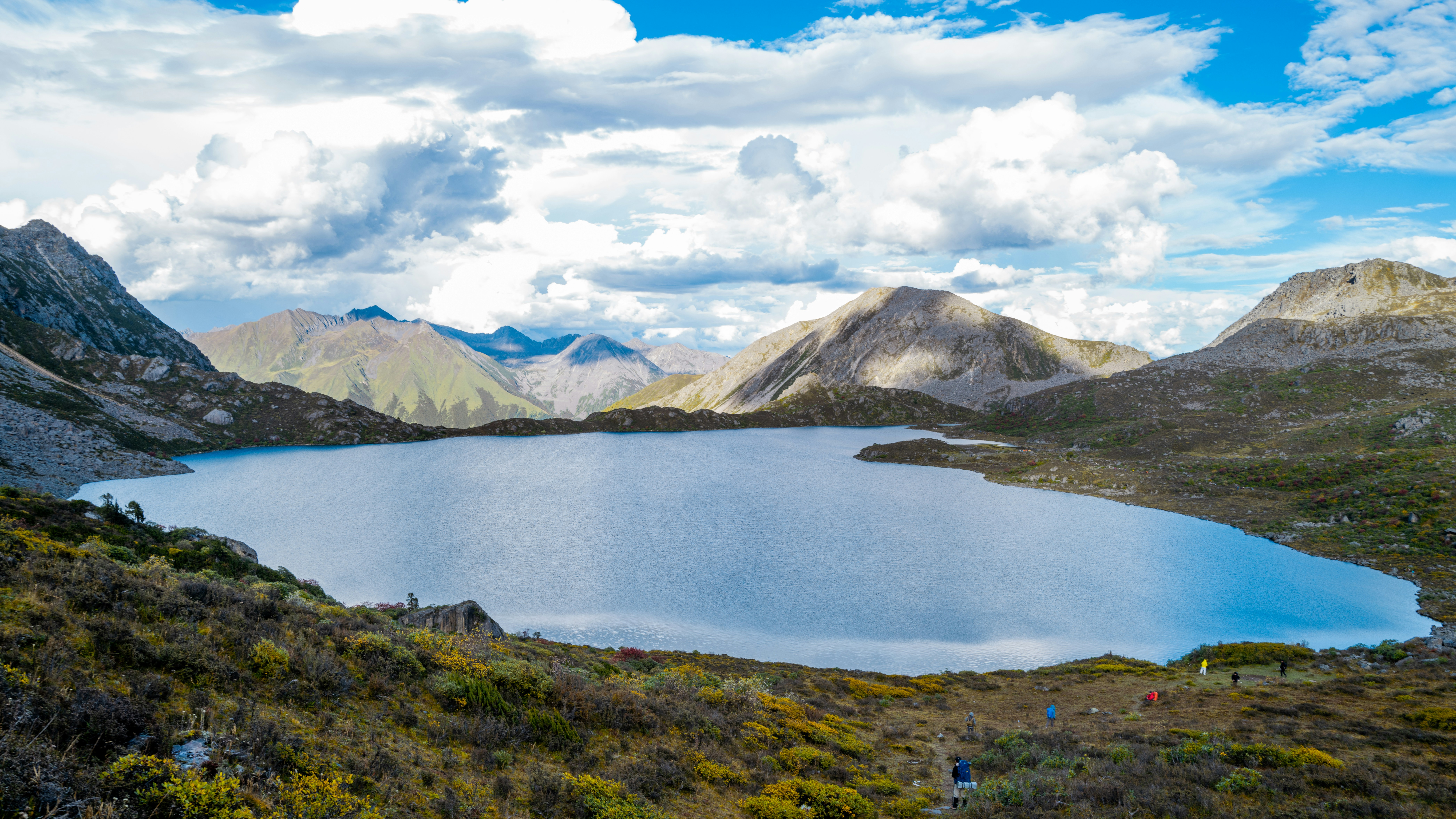 Serene mountain lake surrounded by rocky hills and clouds