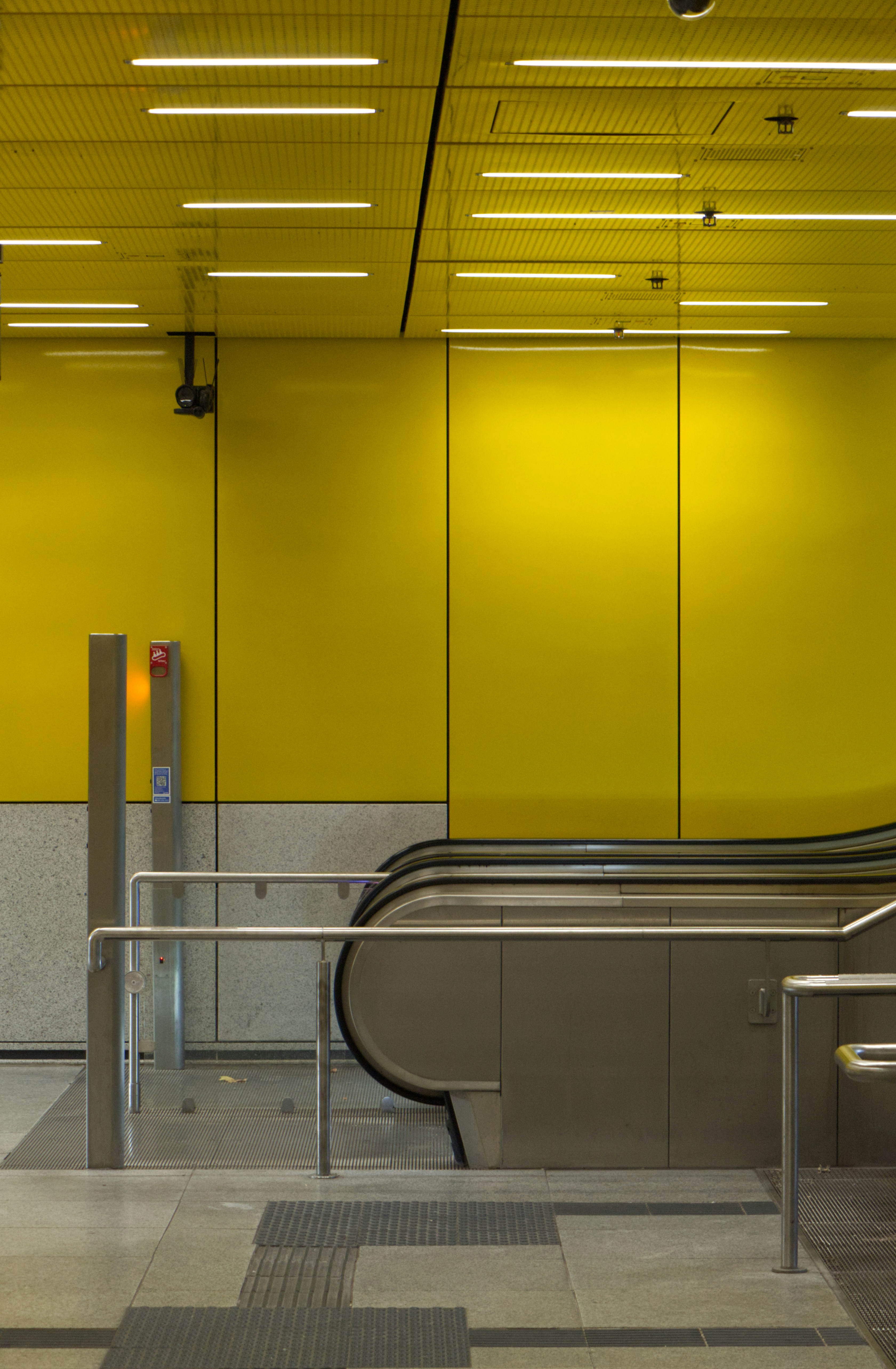 Modern subway station with yellow walls and escalator.