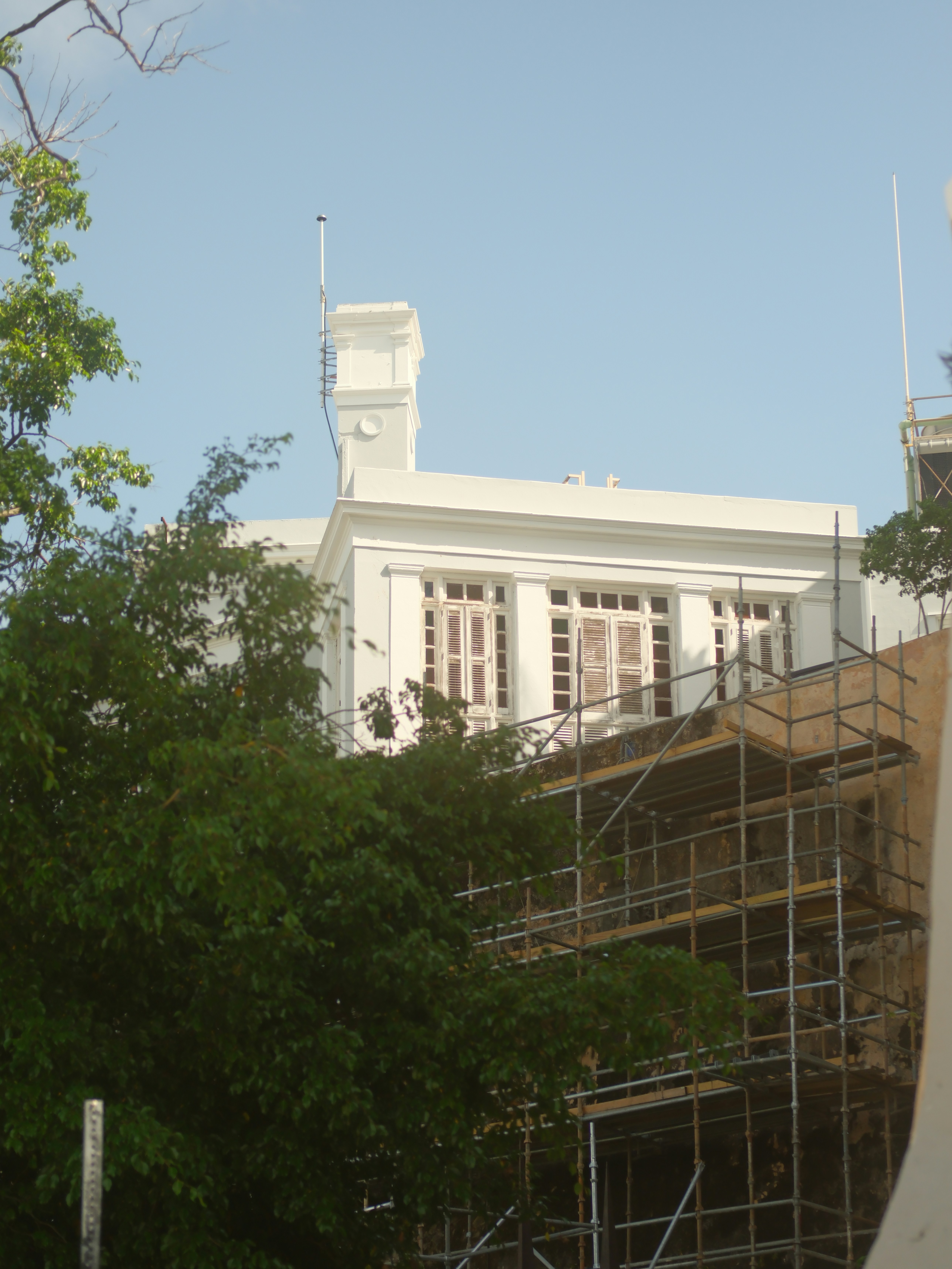 White building with scaffolding and trees