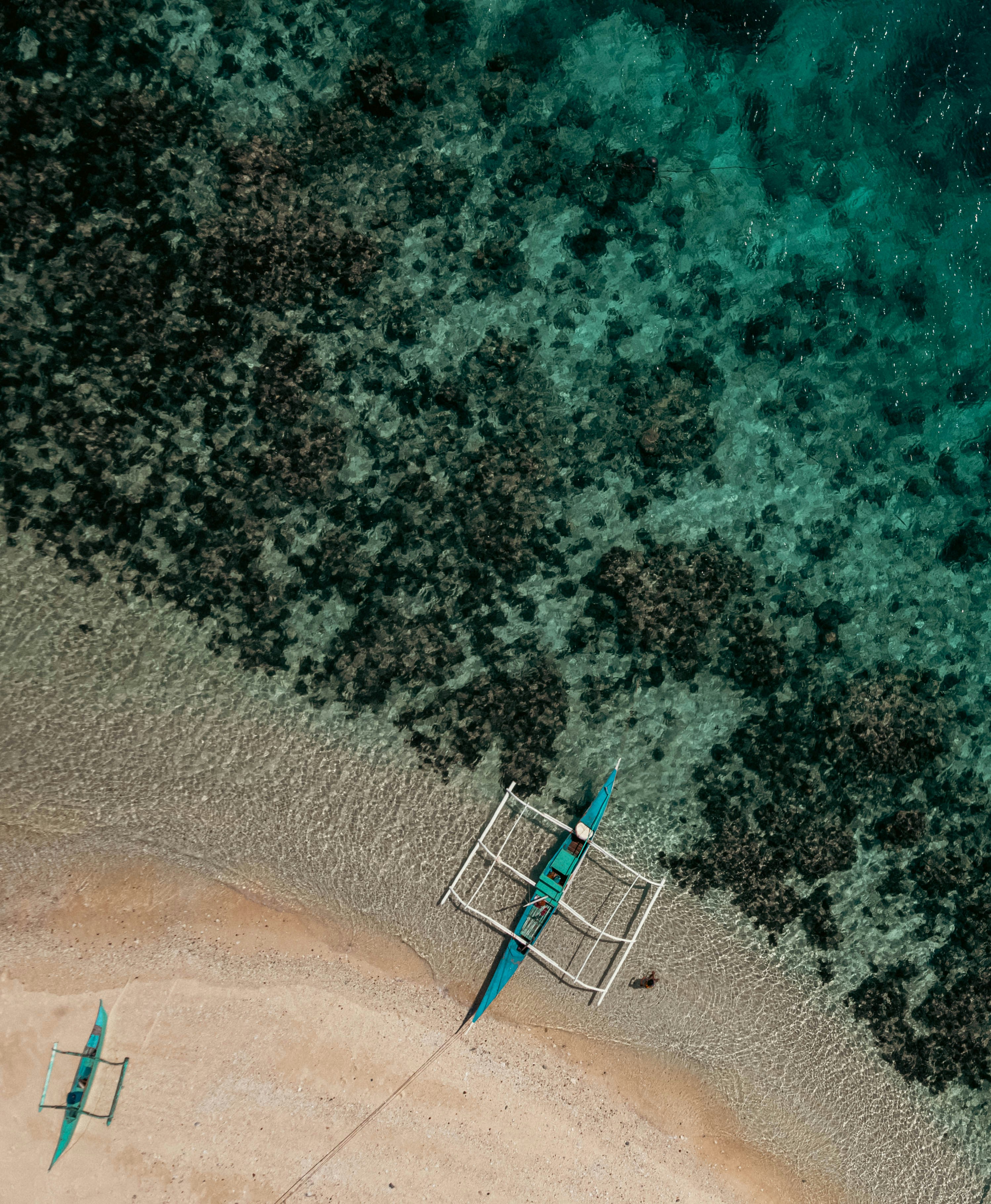 Two boats on a sandy beach near coral reef