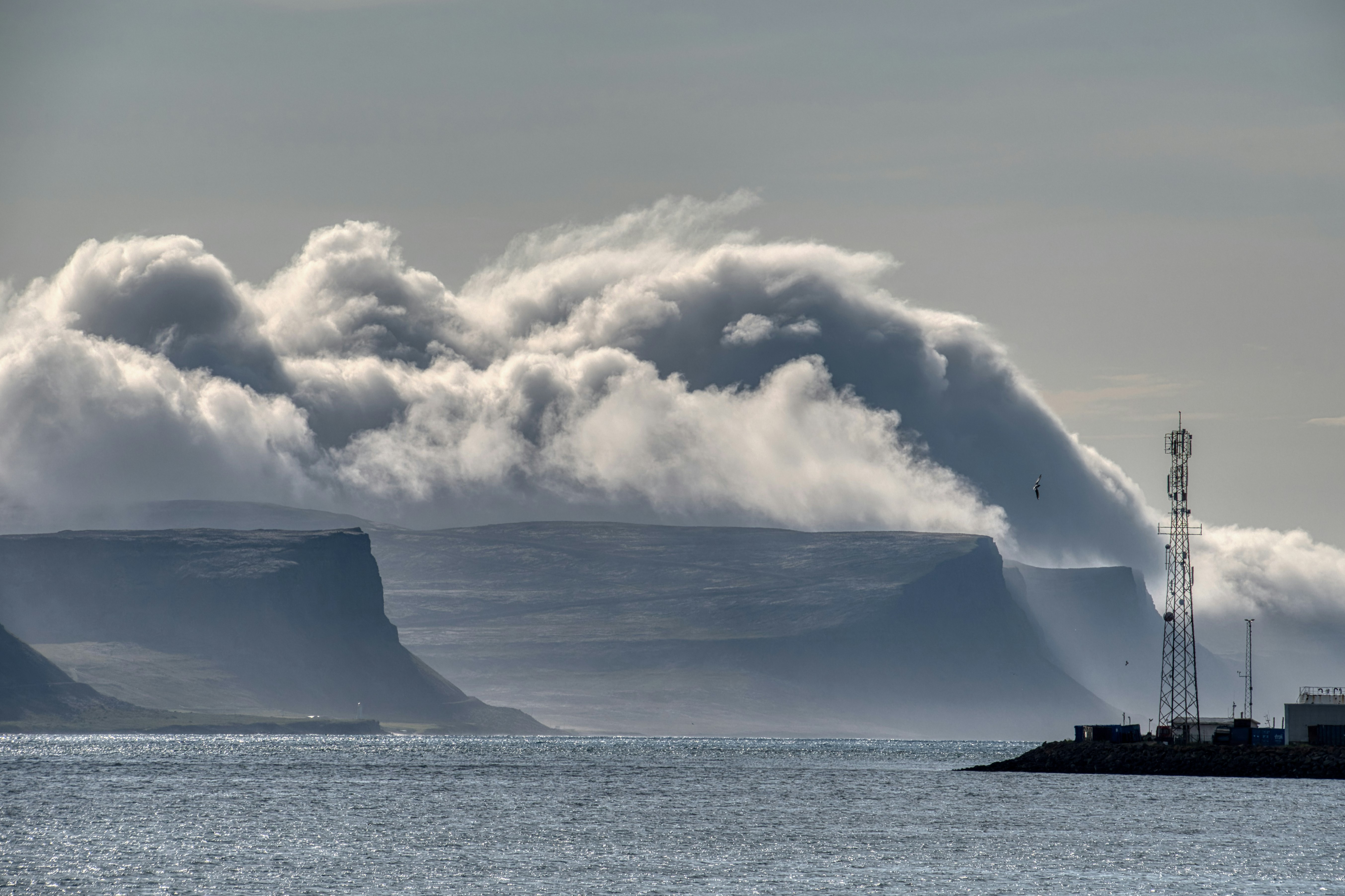 Cloud-Capped Cliffs Framed by a Harbor Mast