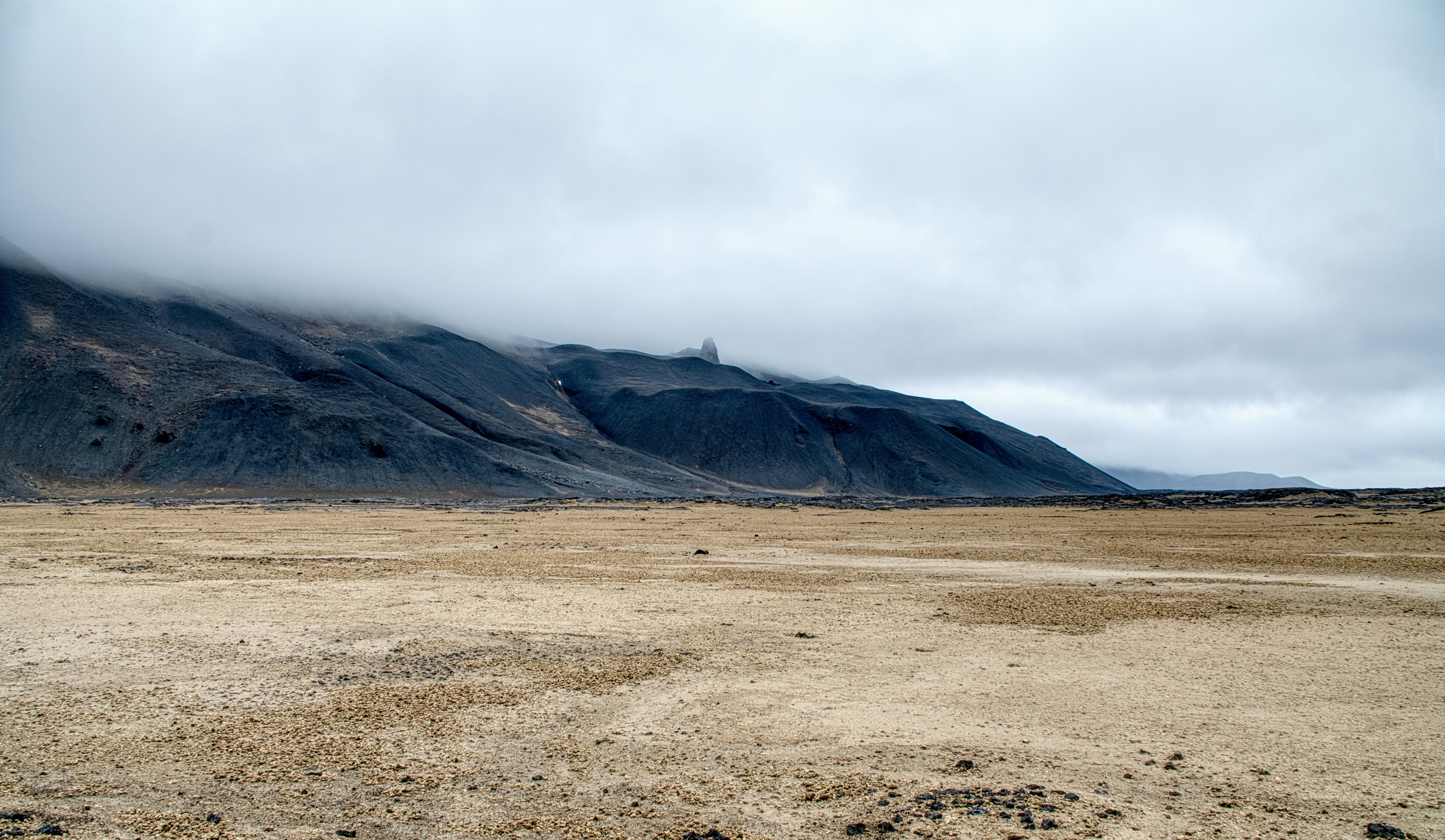 Barren landscape with dark, misty mountains in background.