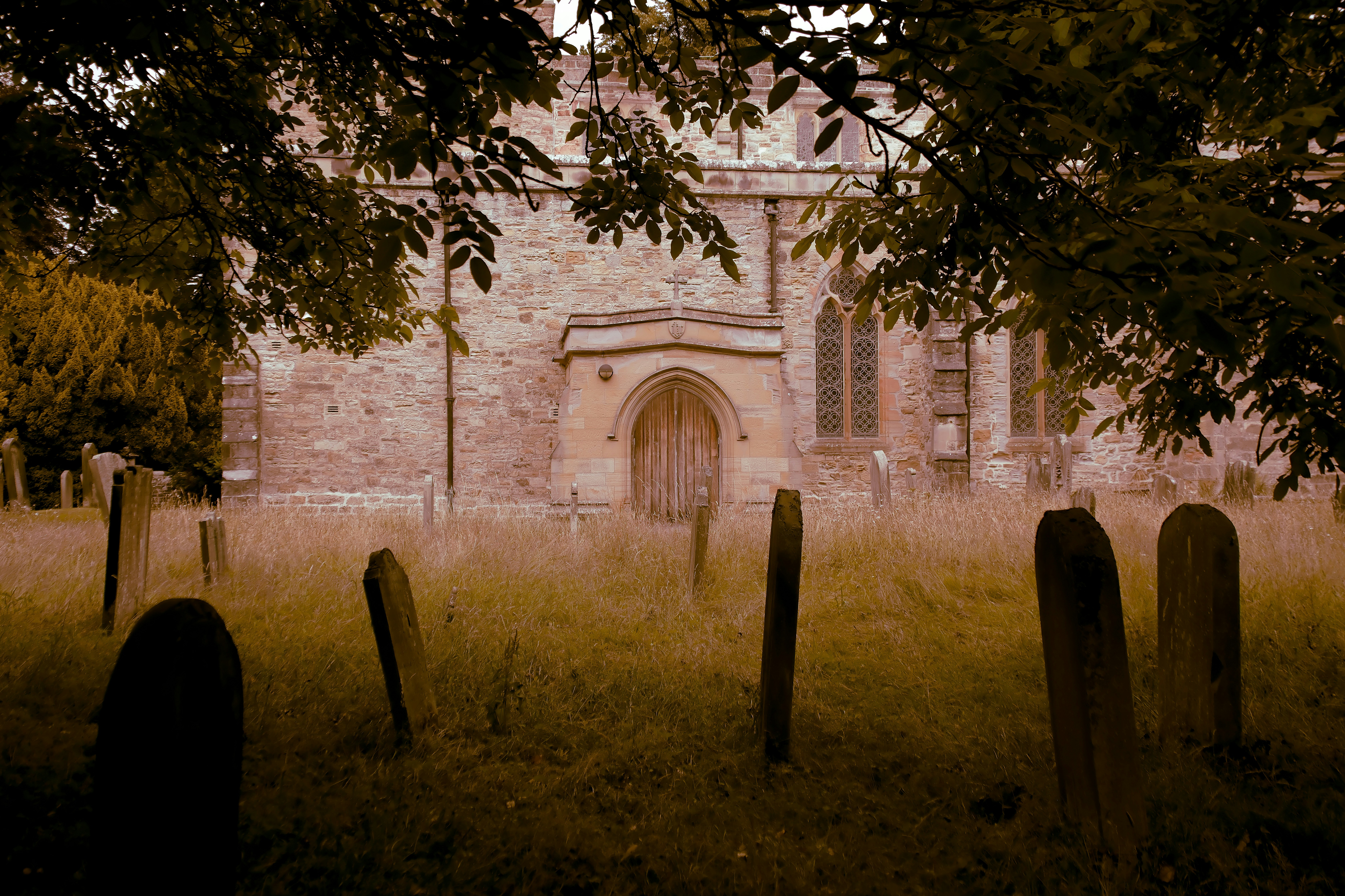 A tranquil, sepia-toned photograph of a historic stone church nestled in a quiet cemetery. | Old gravestones in front of a church building