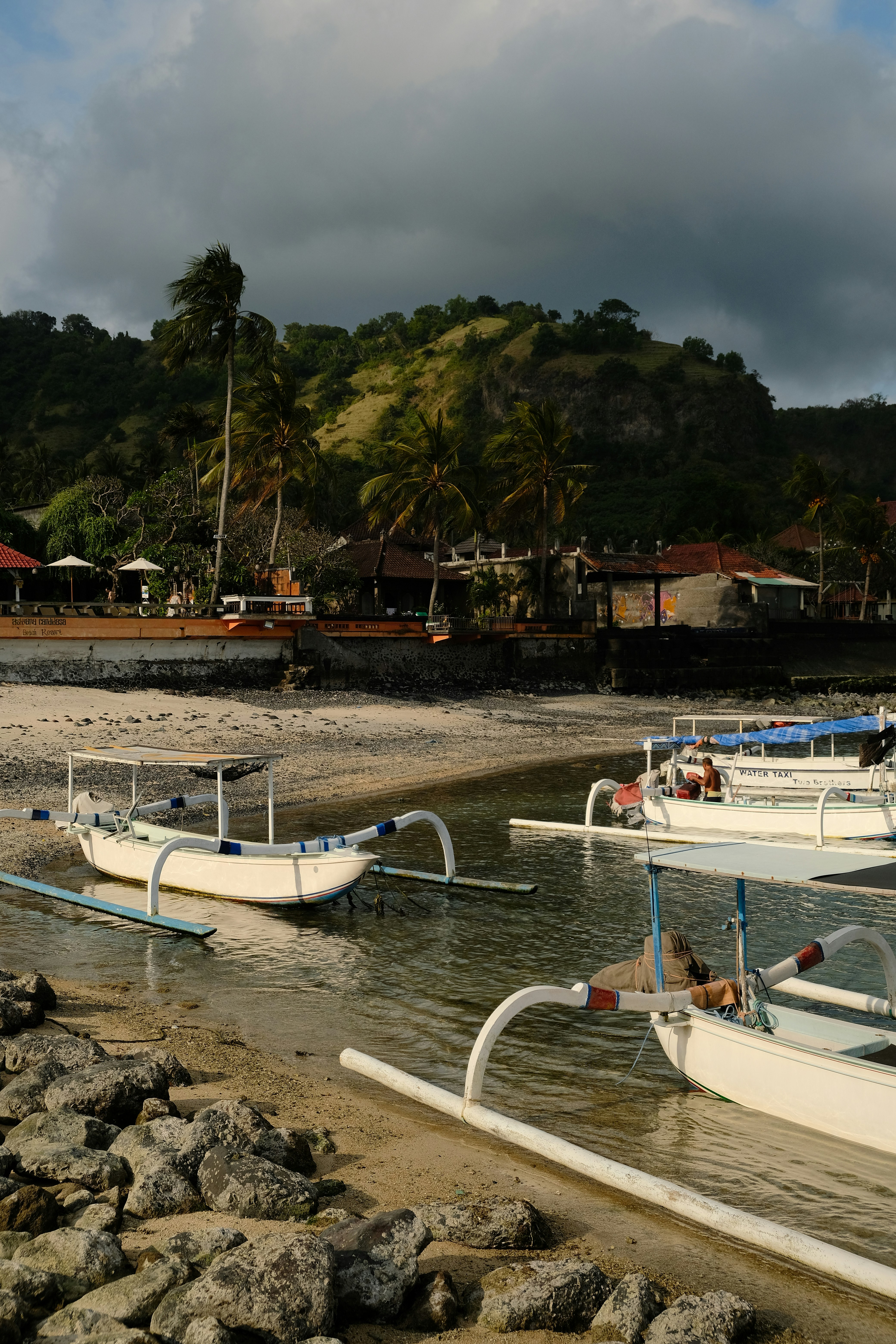 Traditional boats rest on a calm tropical shoreline.