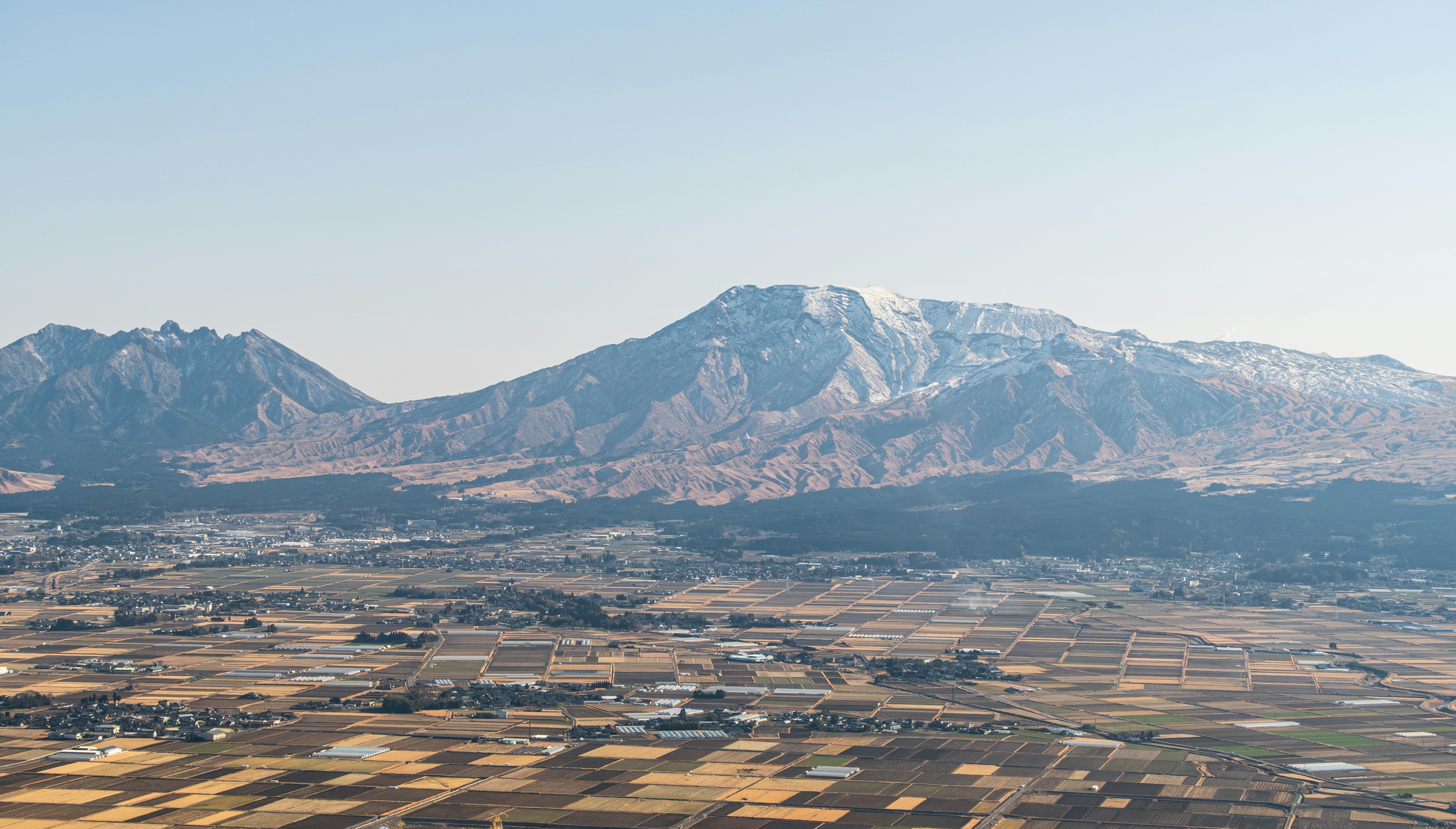 Snow-capped mountains rise above a distant town.