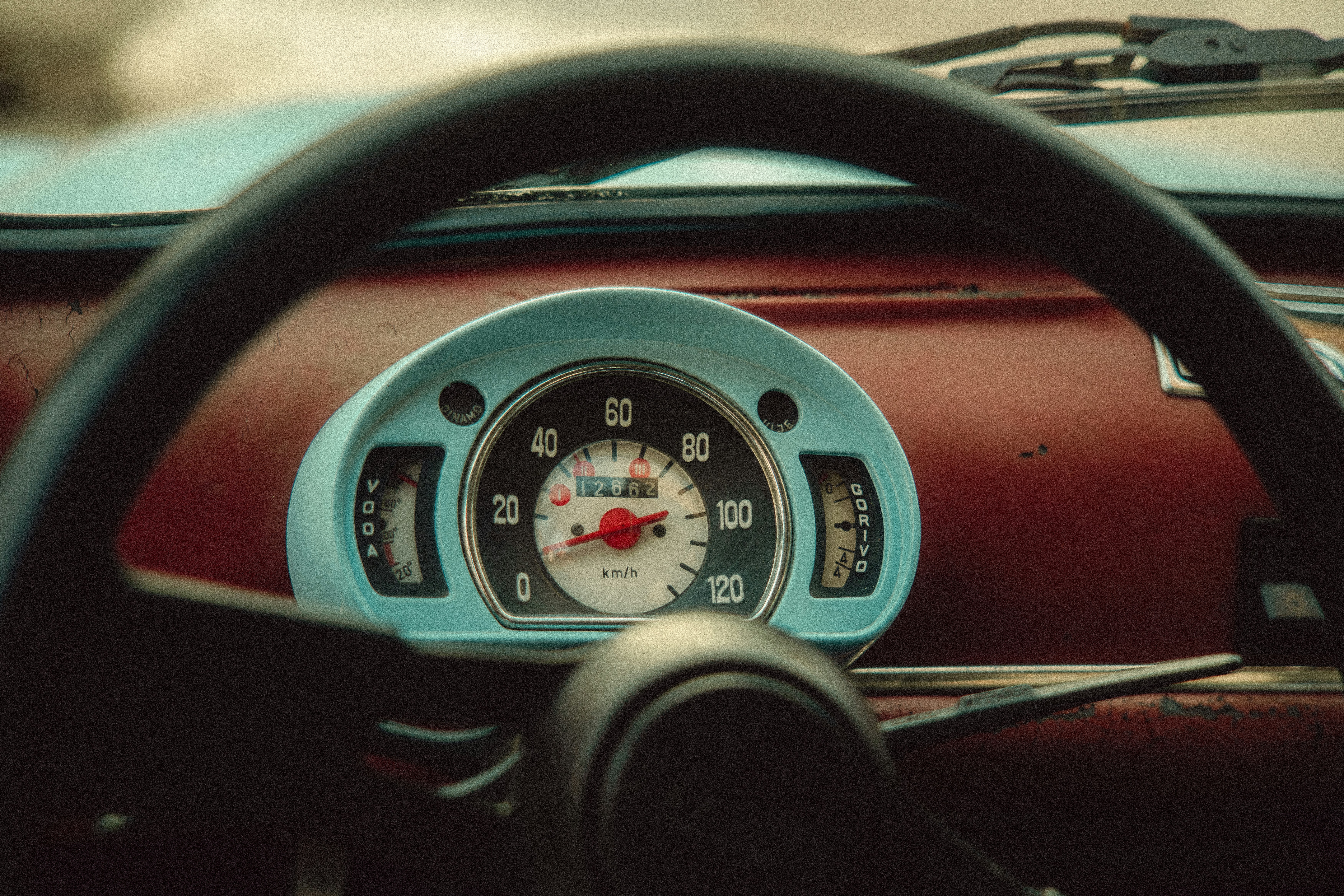 Circular Timekeeper in a Rusty Cabin: Blue Speedometer Framed by the Wheel