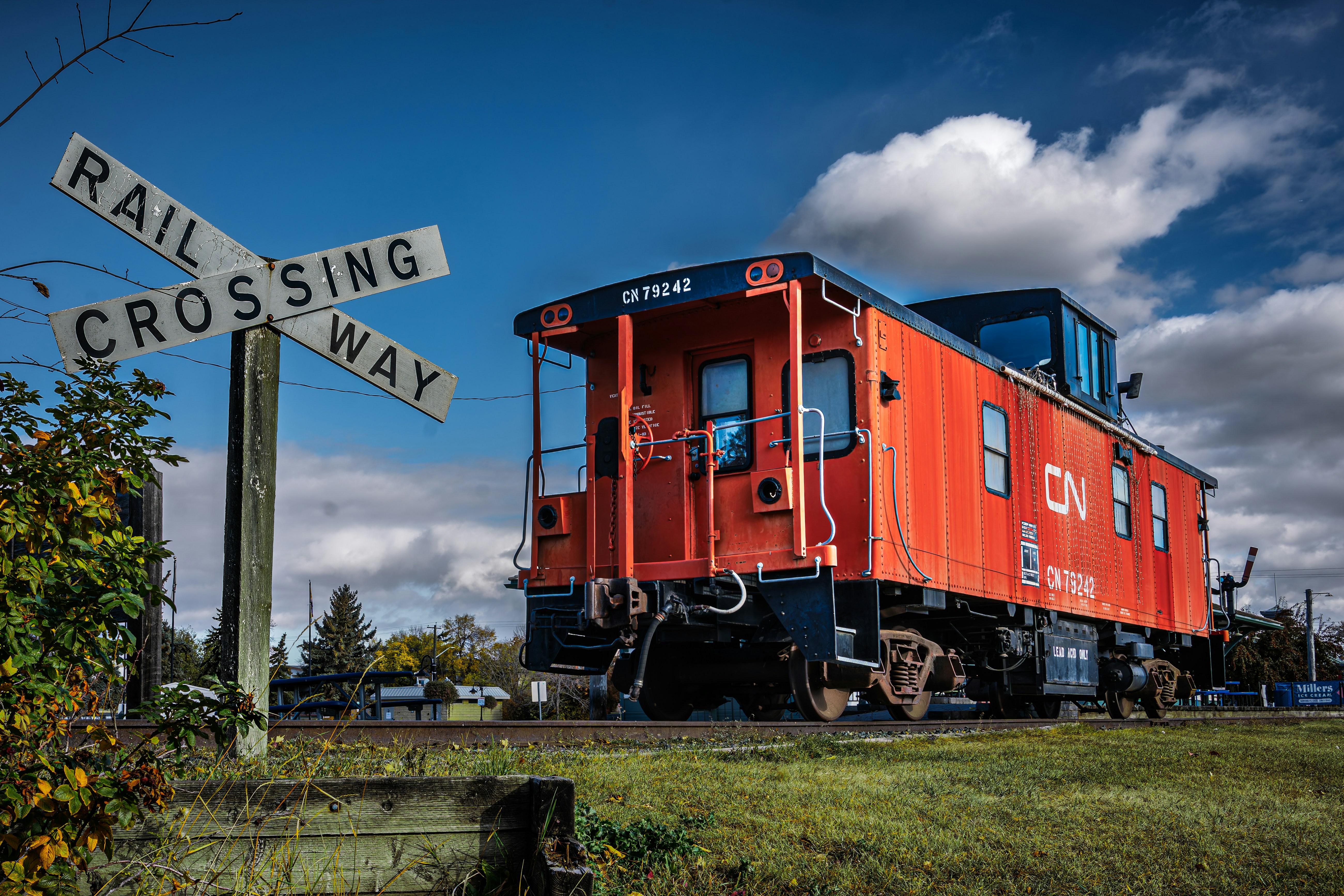 Caboose with railroad crossing sign | Orange caboose at a rail crossing