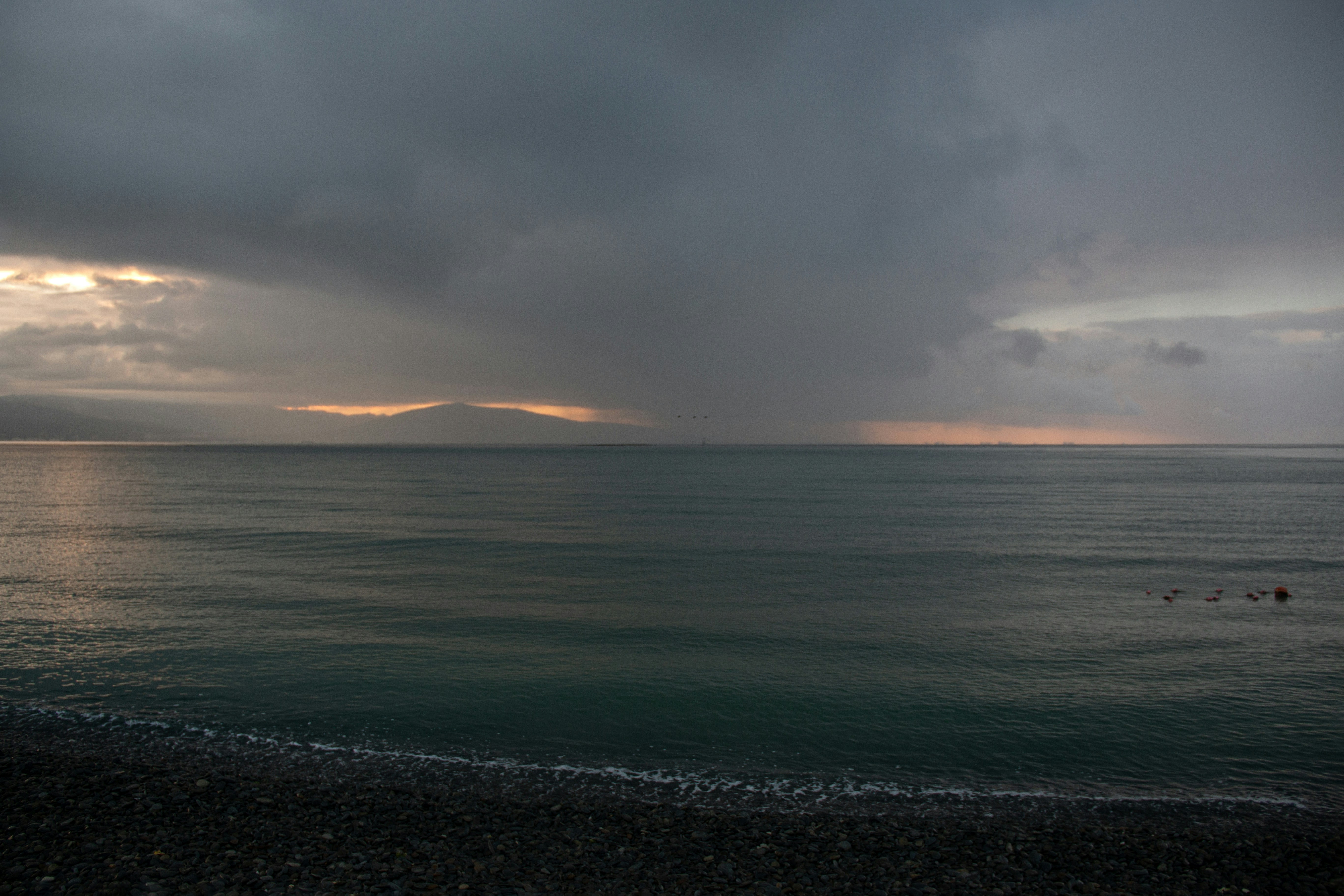 Stormy sunset over the ocean with distant mountains.
