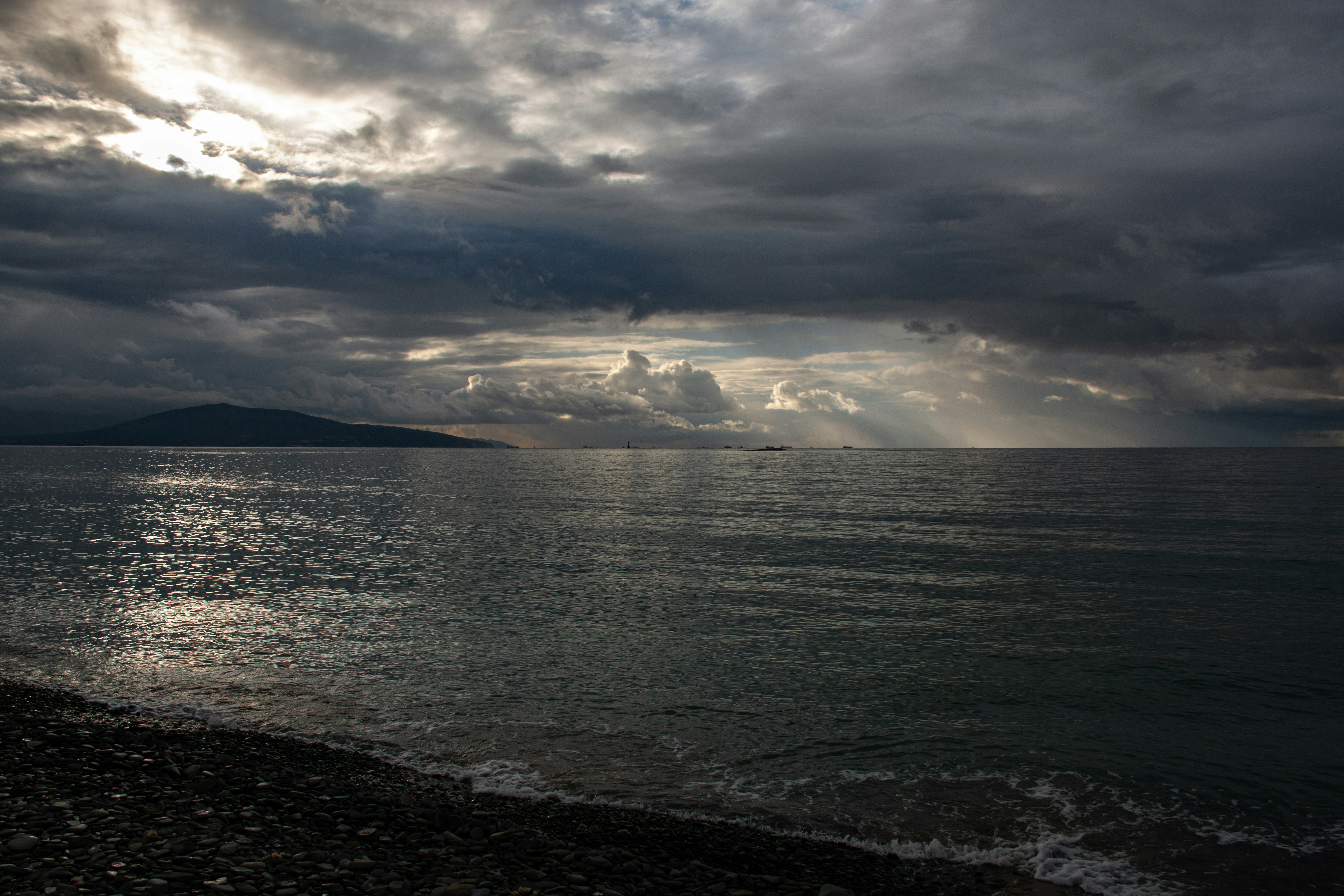 Sunbeams break through stormy clouds over the ocean.