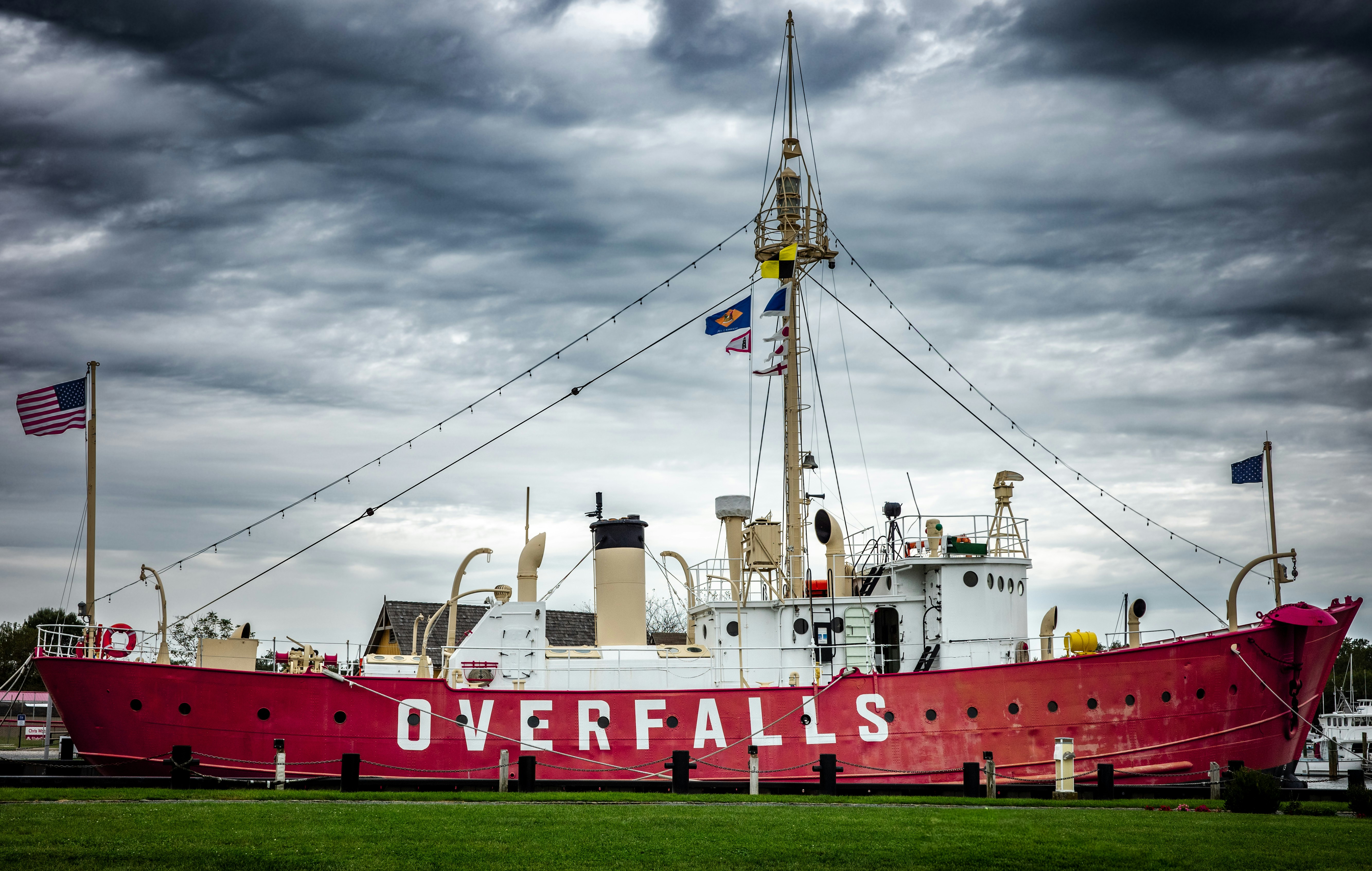 Red ship named overfalls docked under stormy skies.