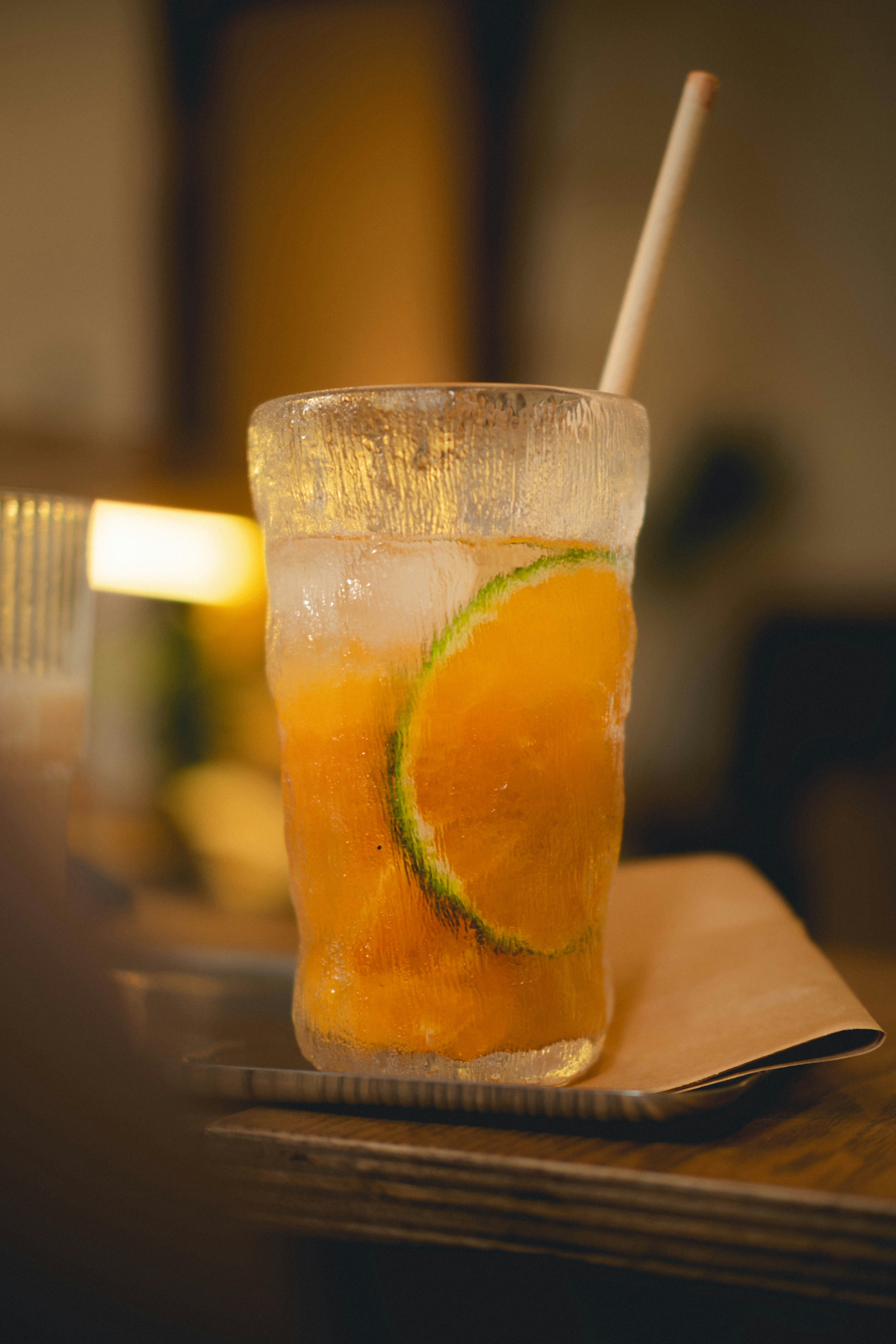 A refreshing orange slice drink with ice and straw.