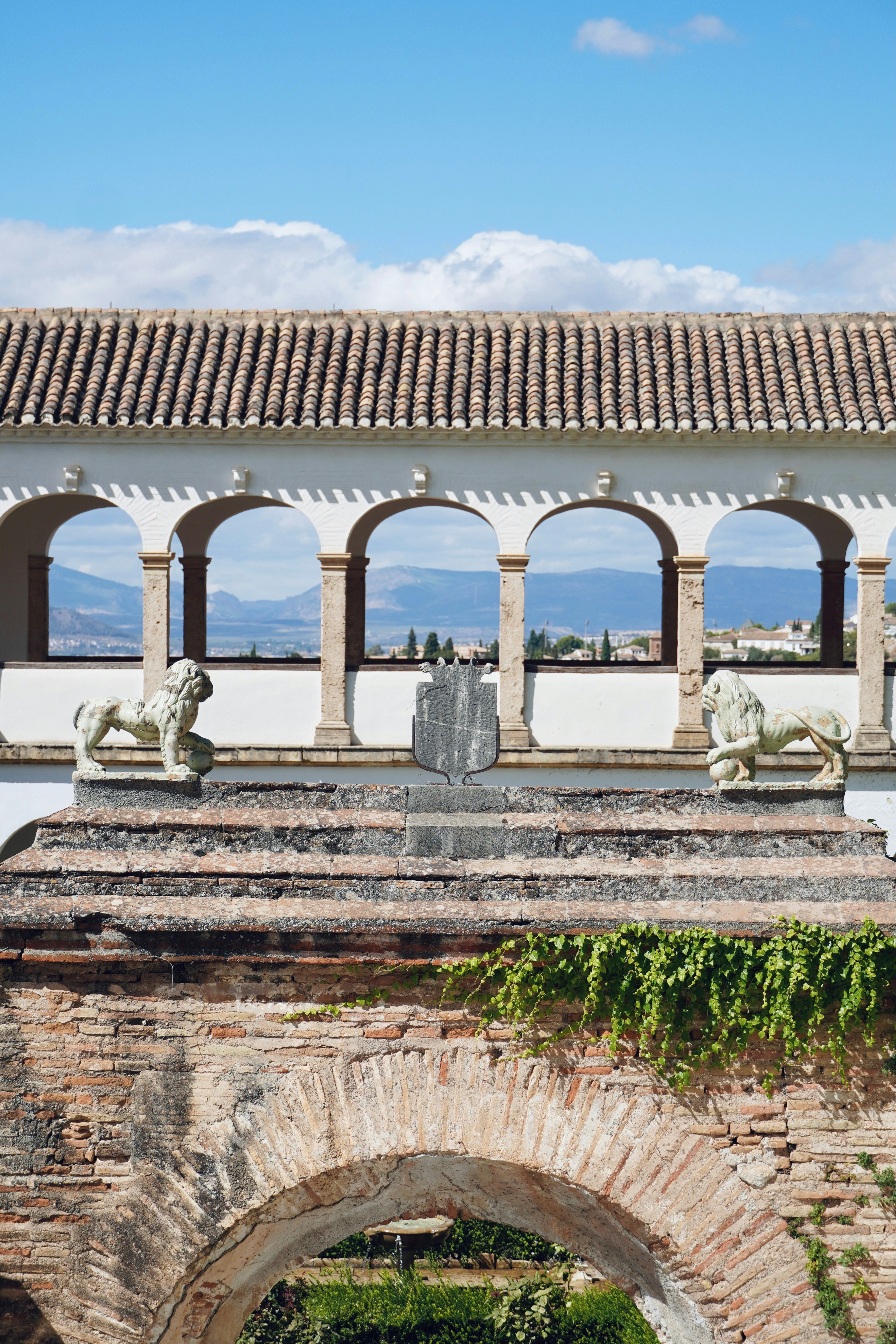 Arched walkway with lion statues overlooking a city.