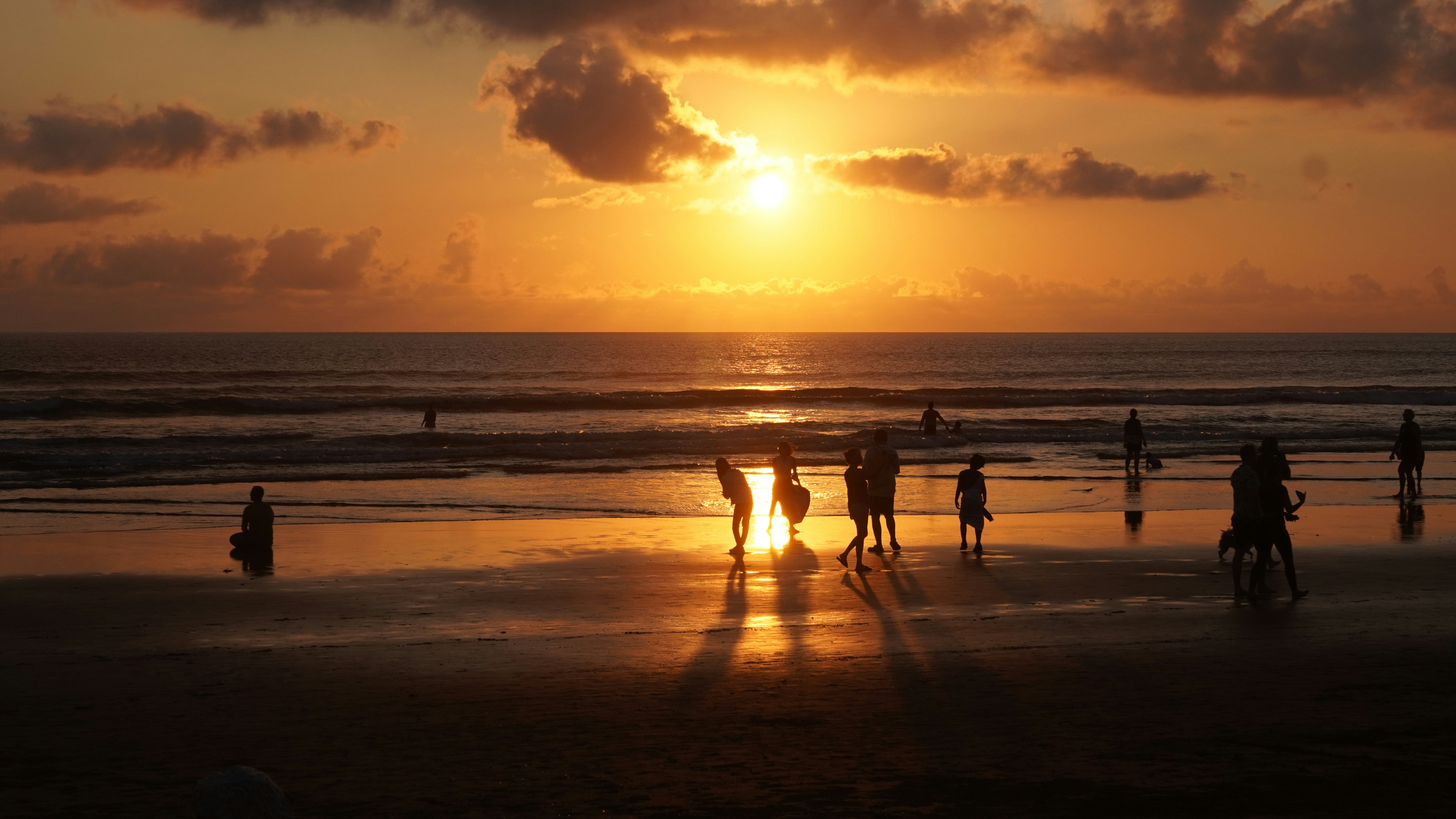 Silhouetted people on a beach at sunset