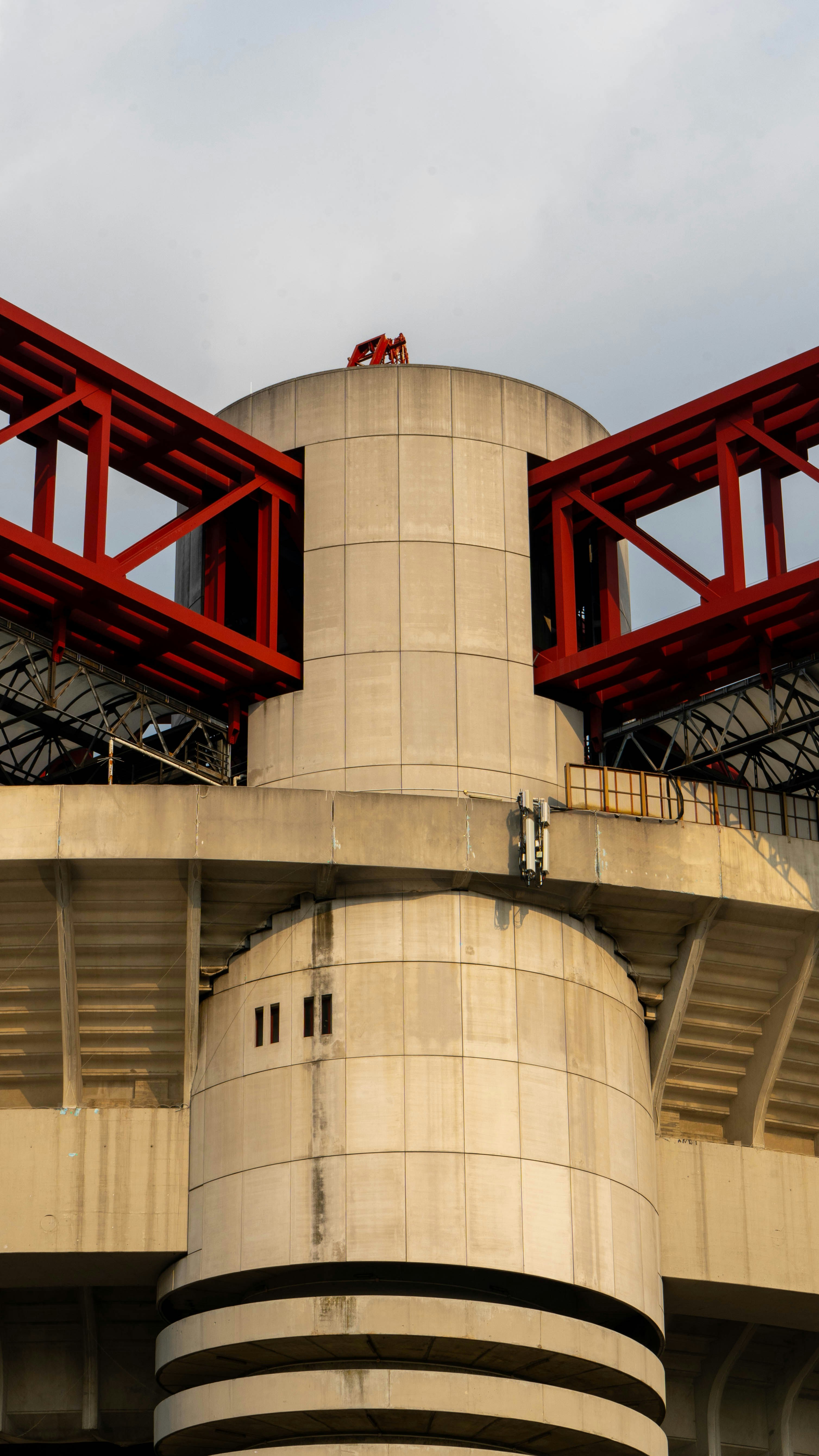 Concrete structure with red beams against cloudy sky