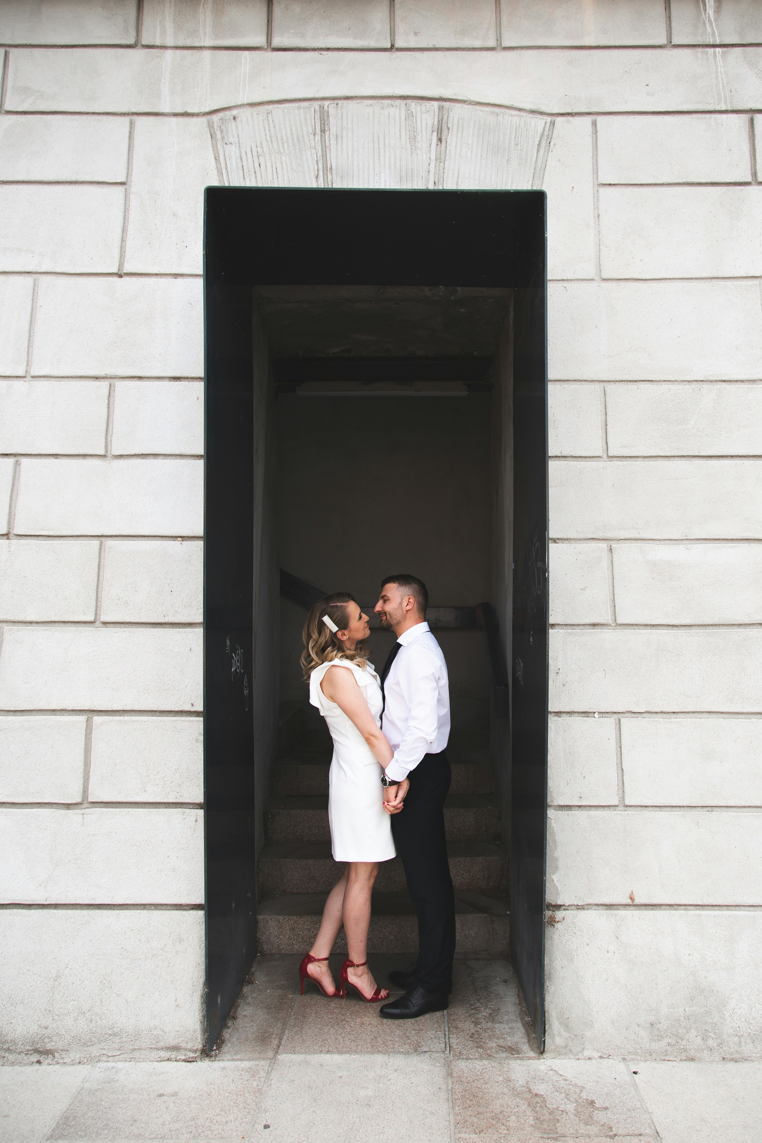 Man and his fiance close together, framed by a door. | Couple holding hands and looking at each other