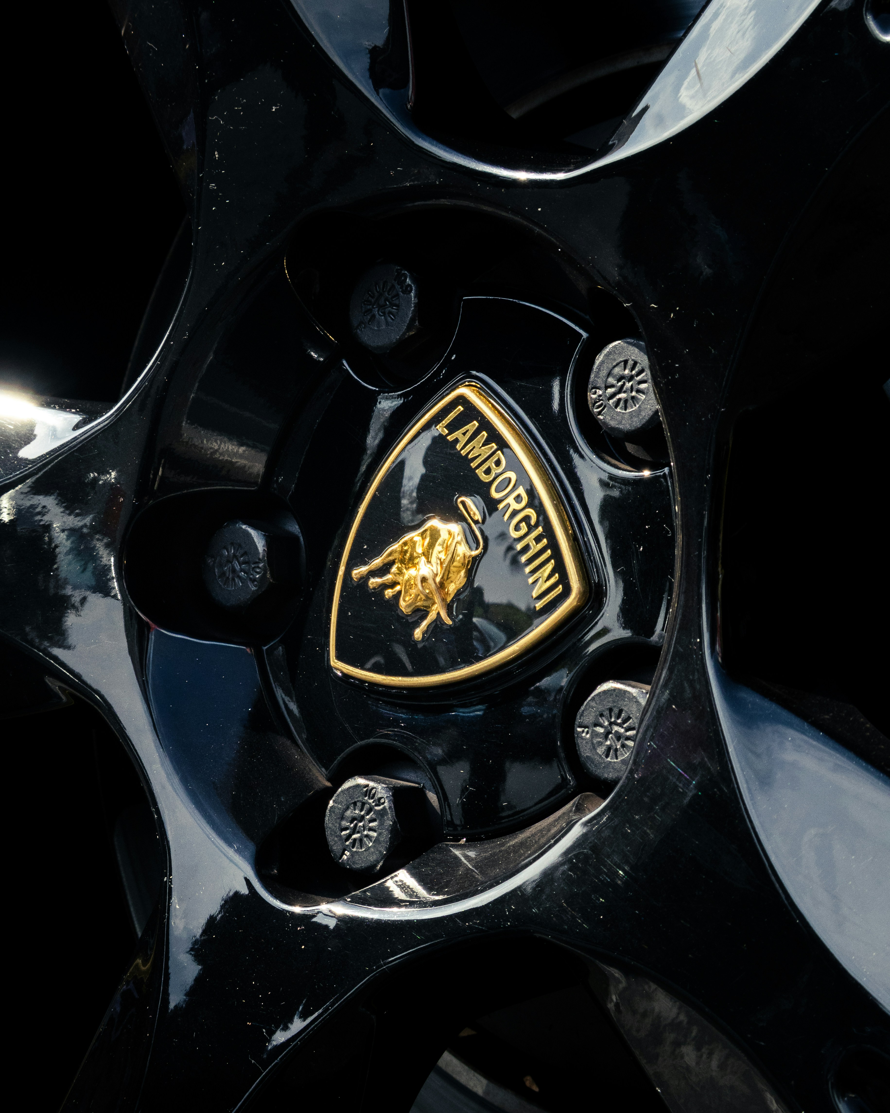 Close-up of a black lamborghini wheel with logo.