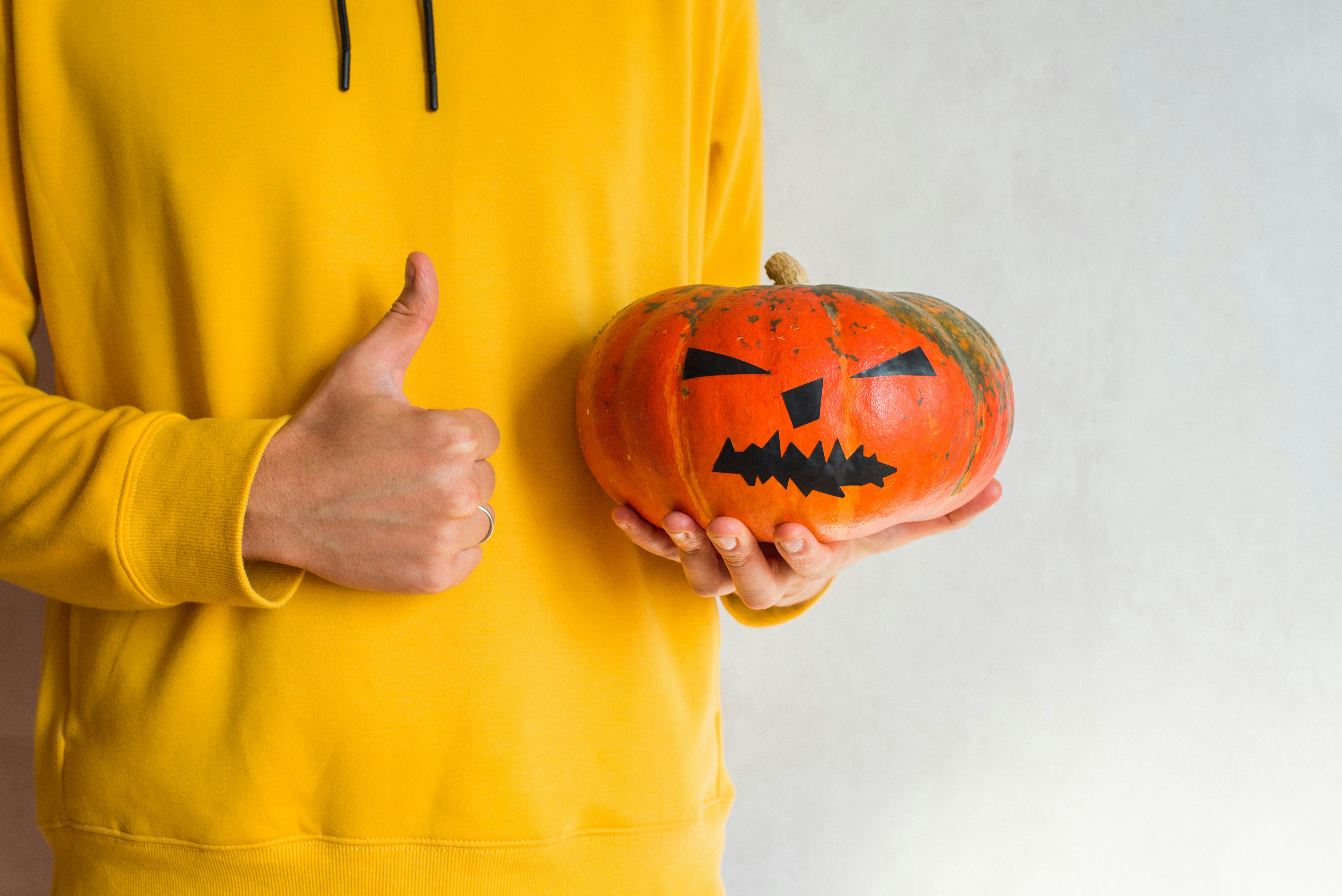 Person in yellow hoodie holding carved pumpkin photo – Free Autumn ...