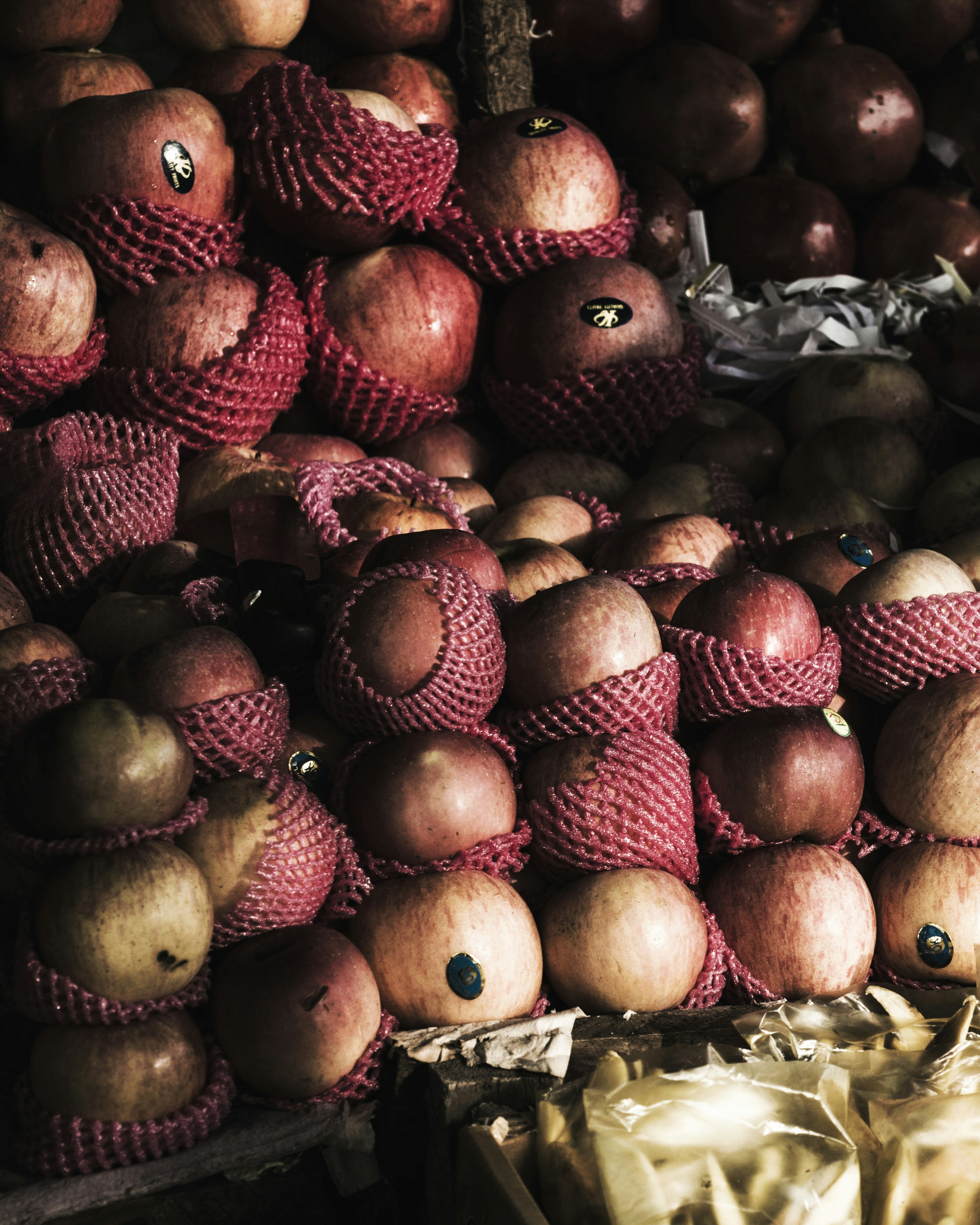 apples stocked at a market | Red apples stacked and wrapped in protective netting.