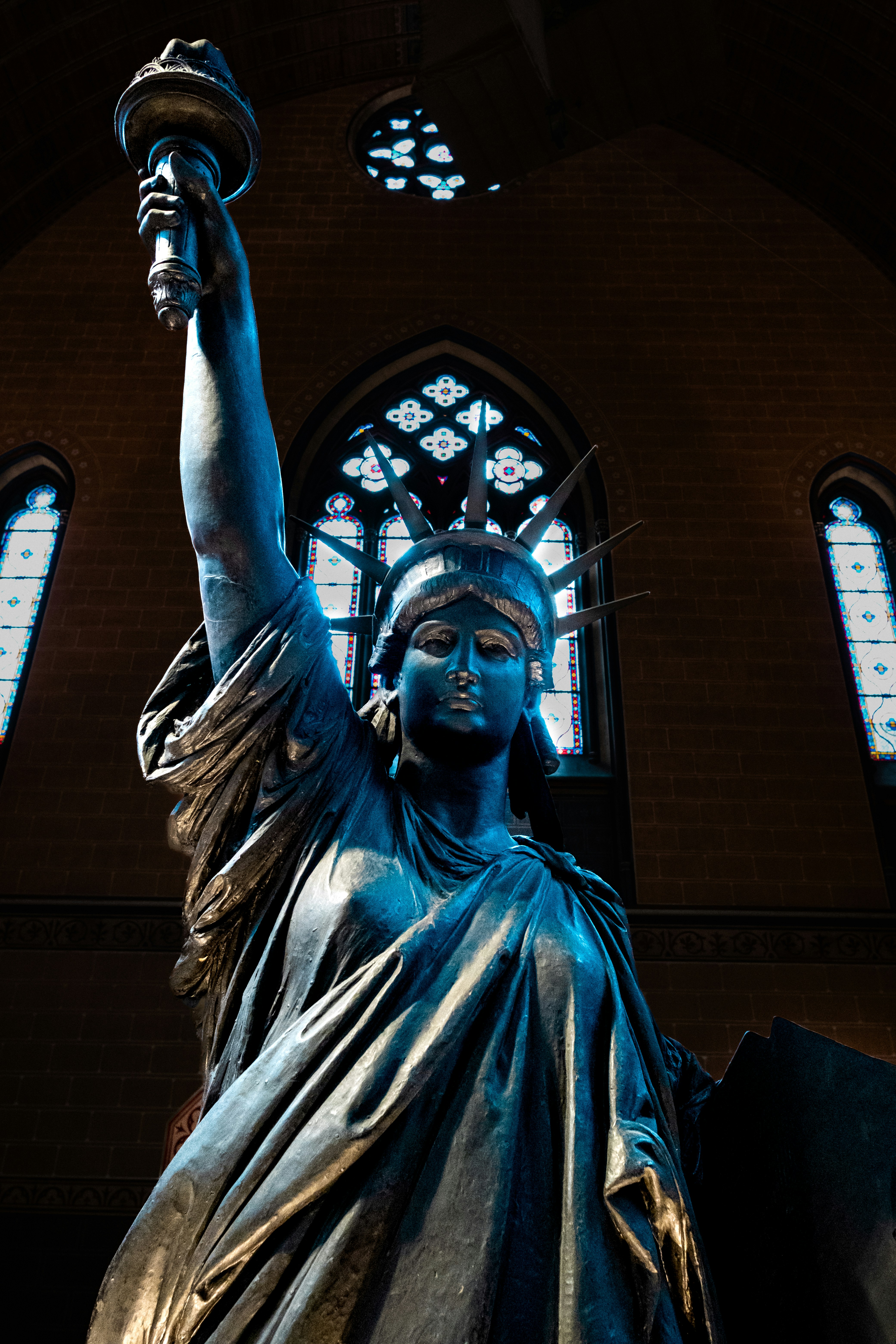 Statue of liberty replica indoors with stained glass windows