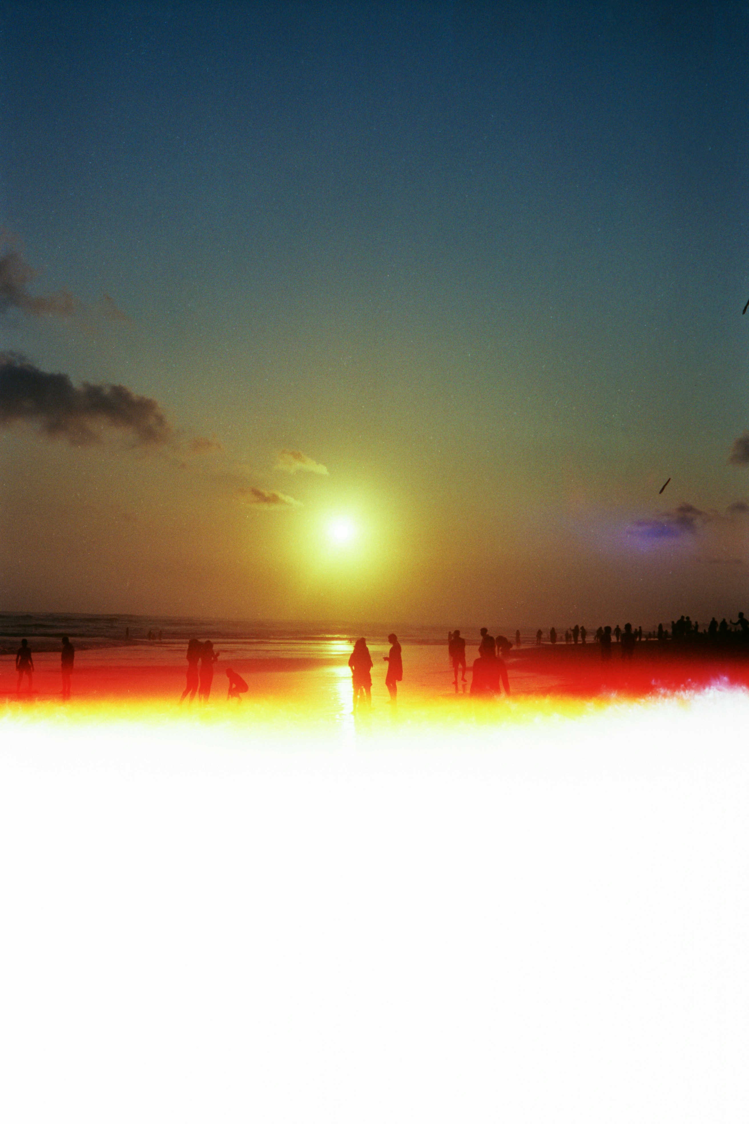 Cinestilı 400d 🎞️ | Silhouetted people on beach at sunset with lens flare.
