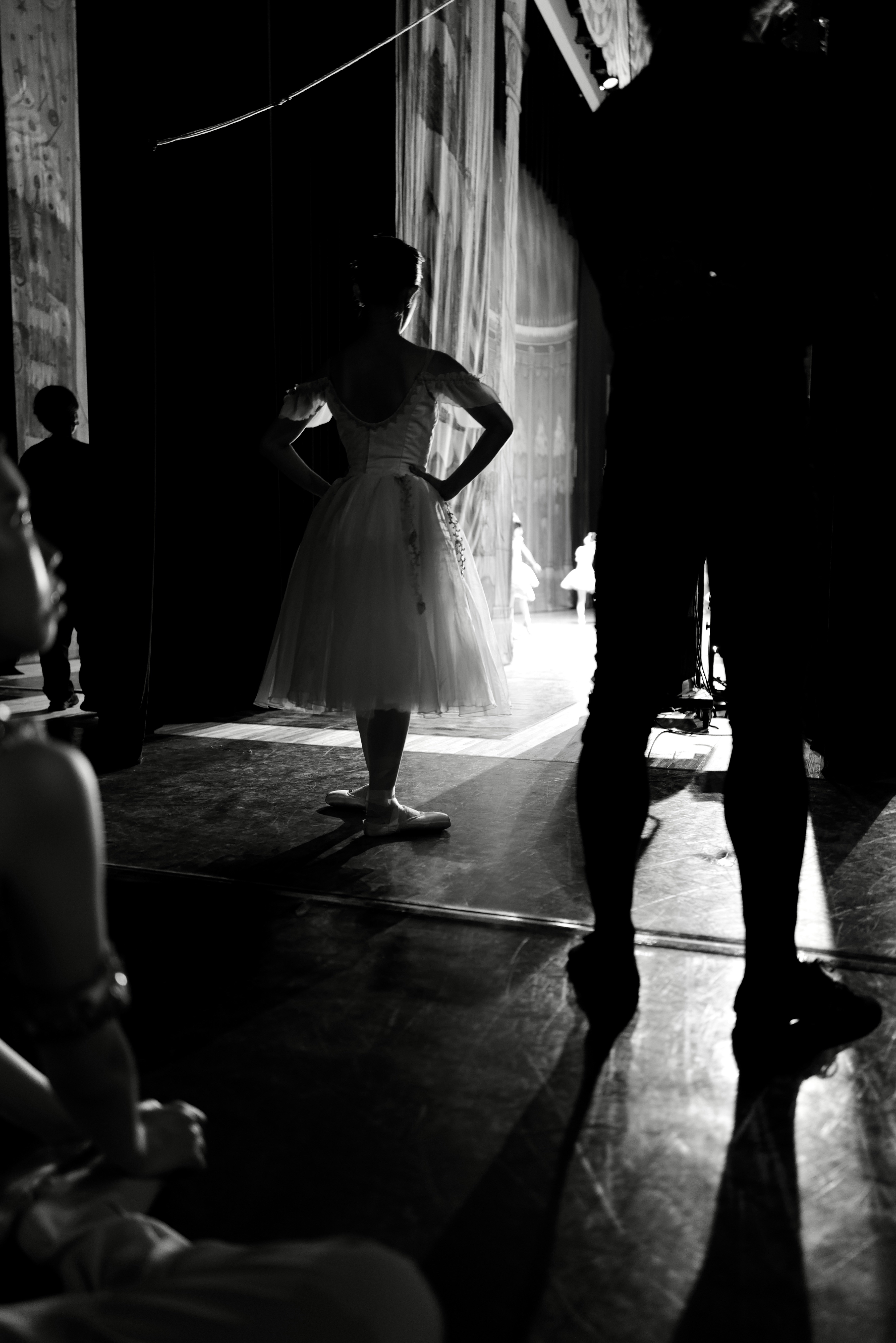 Ballerina waits on stage in dramatic lighting.
