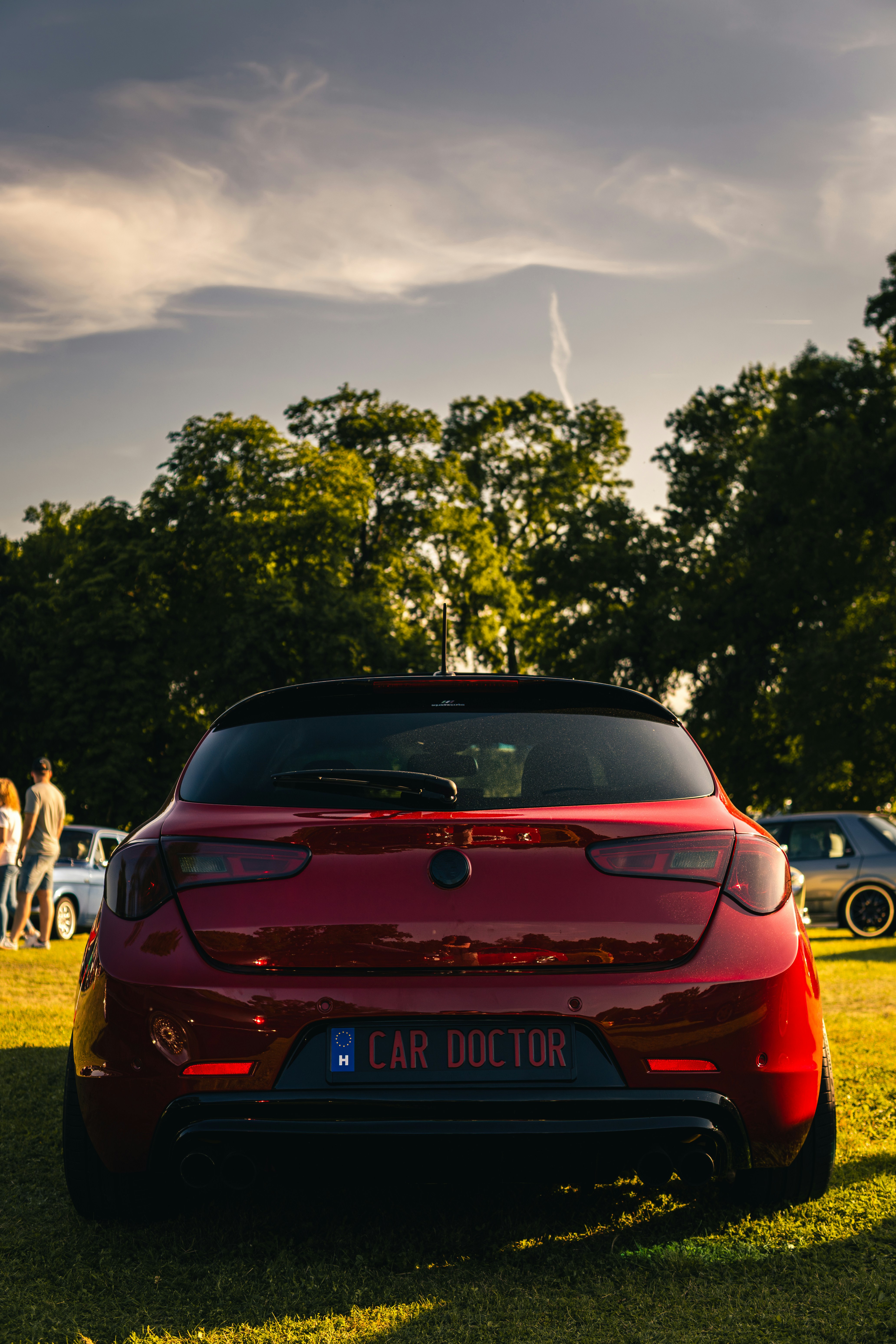 Red Hatchback at Golden Hour: CAR DOCTOR Plate Anchors a Parkside Scene