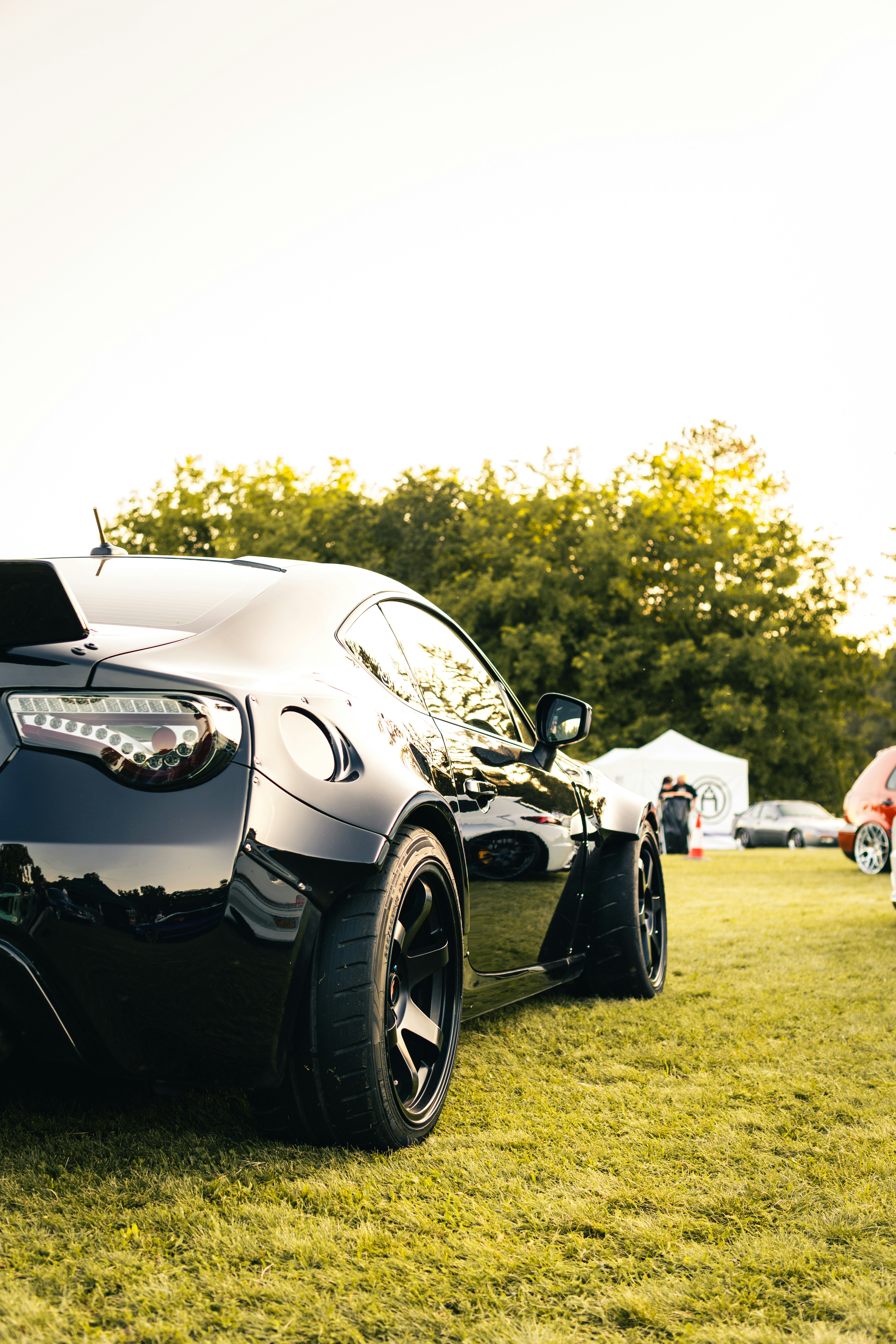 Gloss and Shadow: A midnight coupe at a sunlit car show