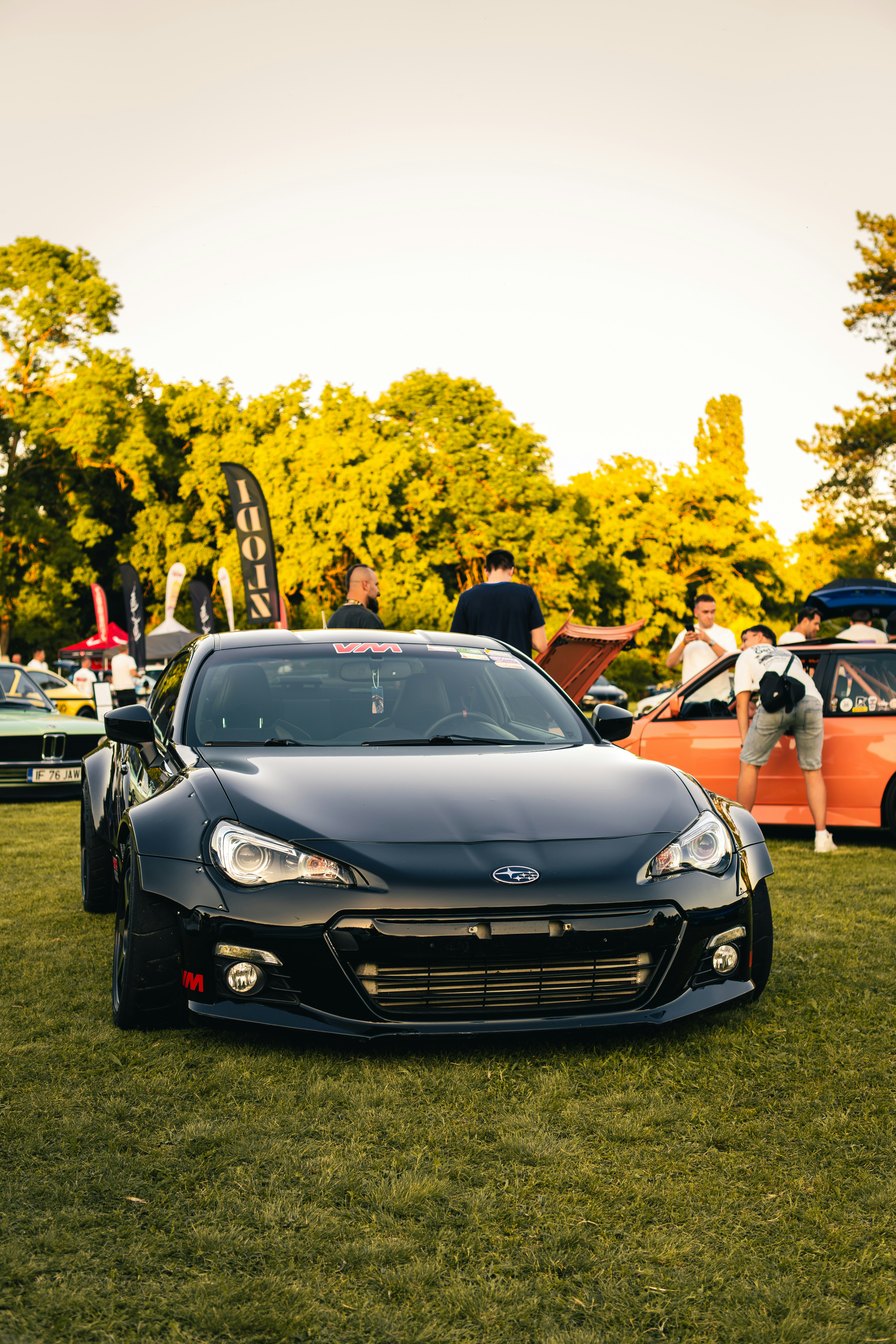 Front-Row Momentum: A Black Subaru Commands a Golden-Hour Car Show