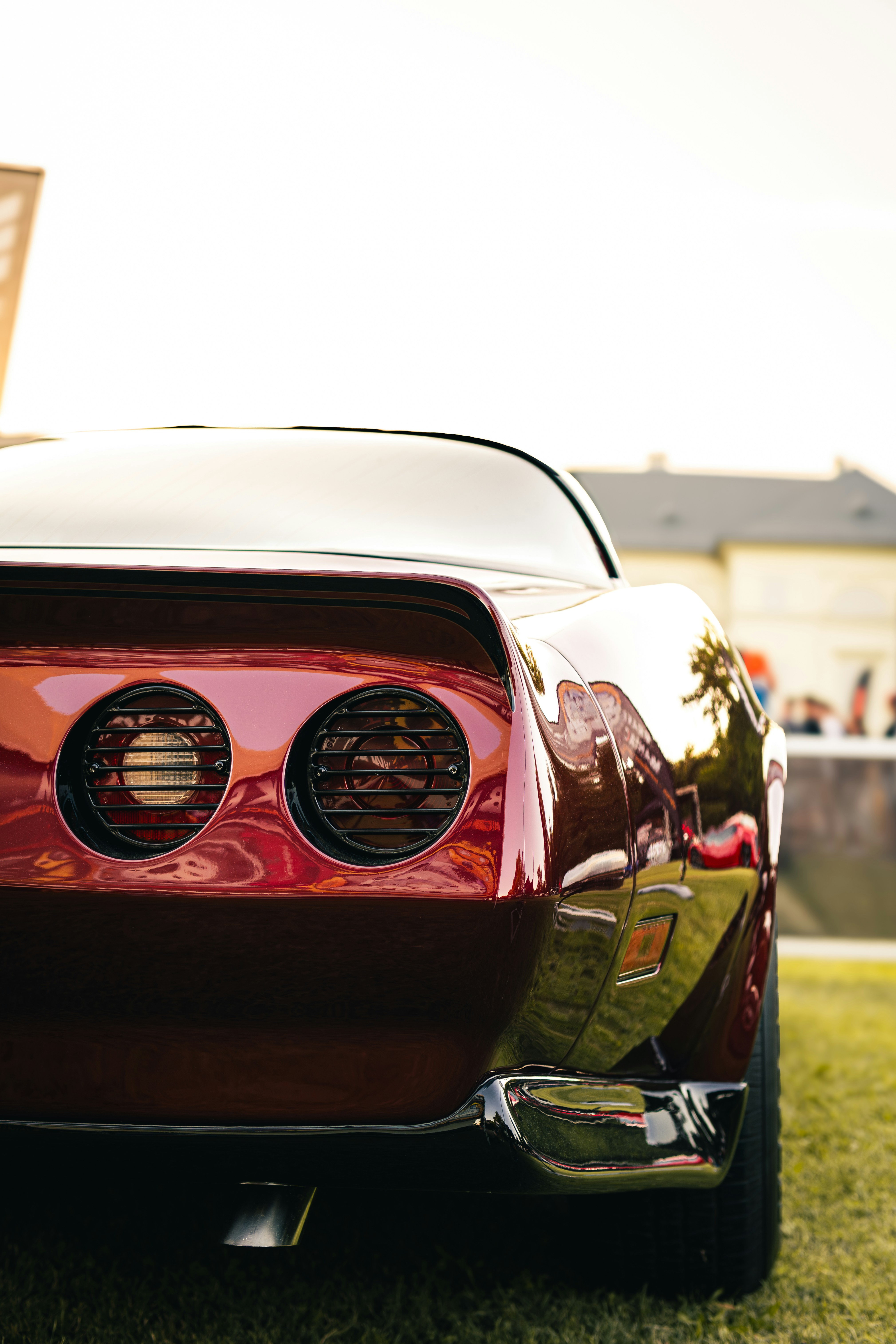 Sunlit Curves: A maroon sports car's circular taillights and glossy rear